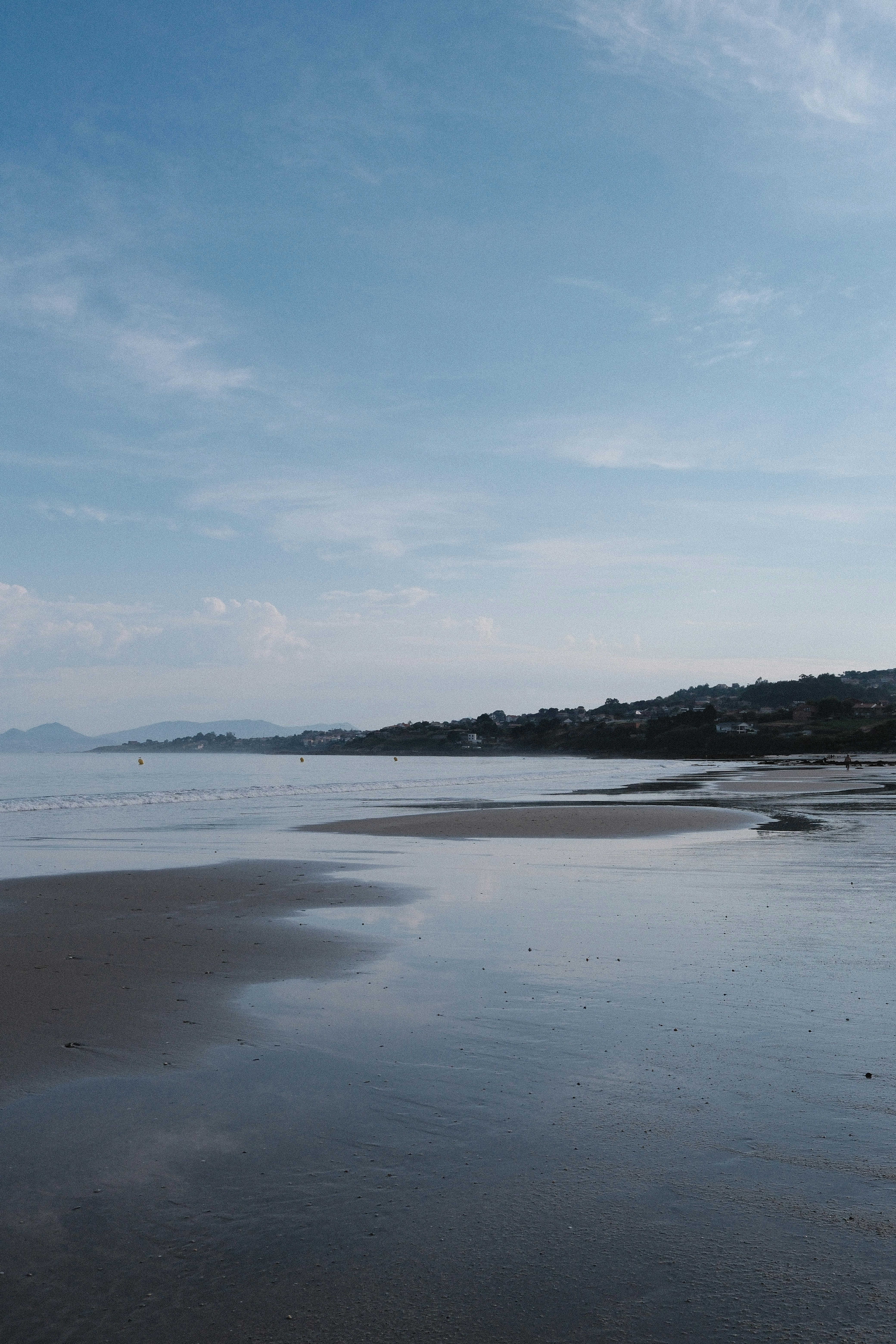 Quiet Shoreline at Dusk: Gentle Tide and Distant Town