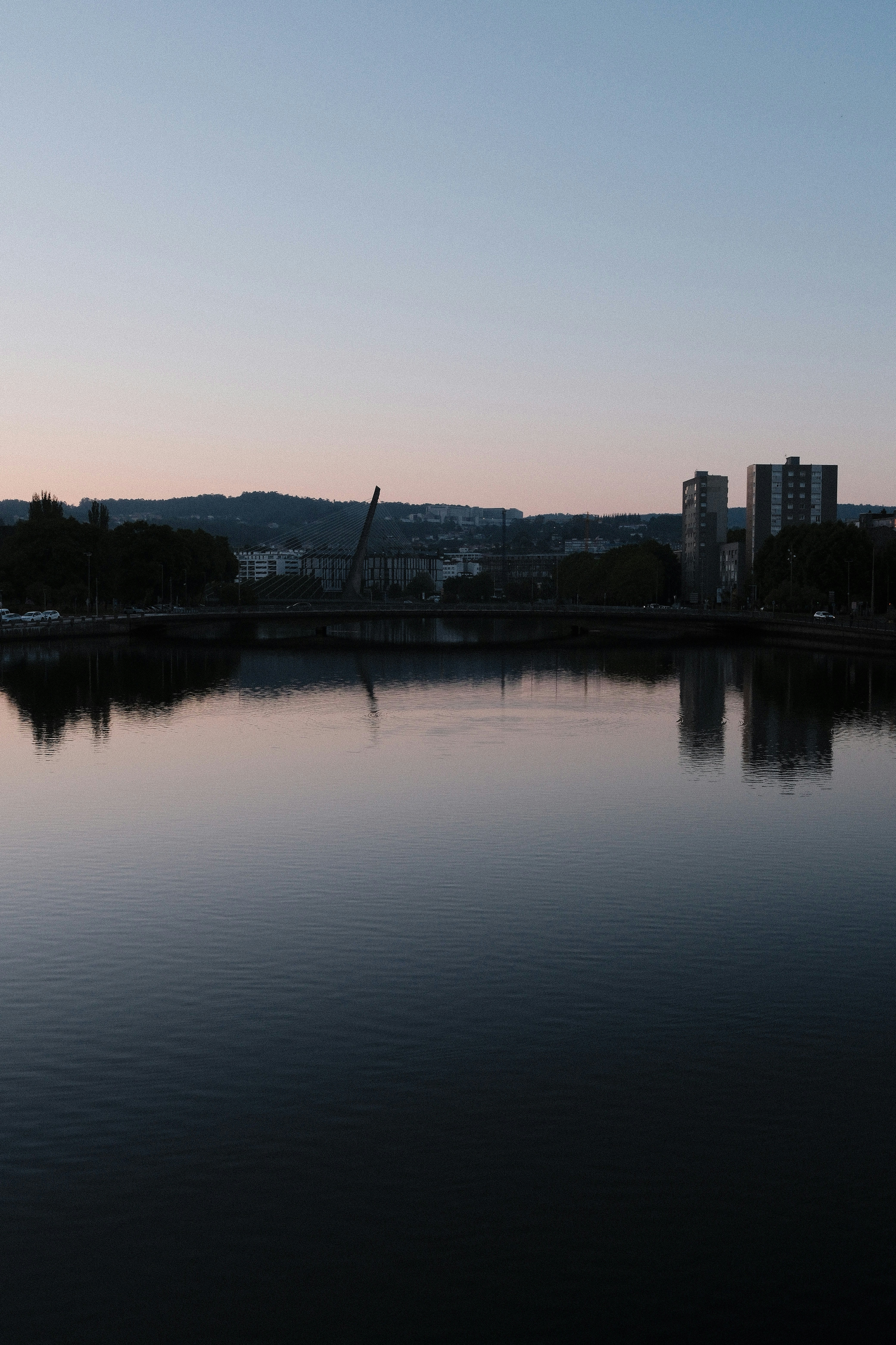 Dusk over the Quiet River: Bridges and Skyline in Silhouette