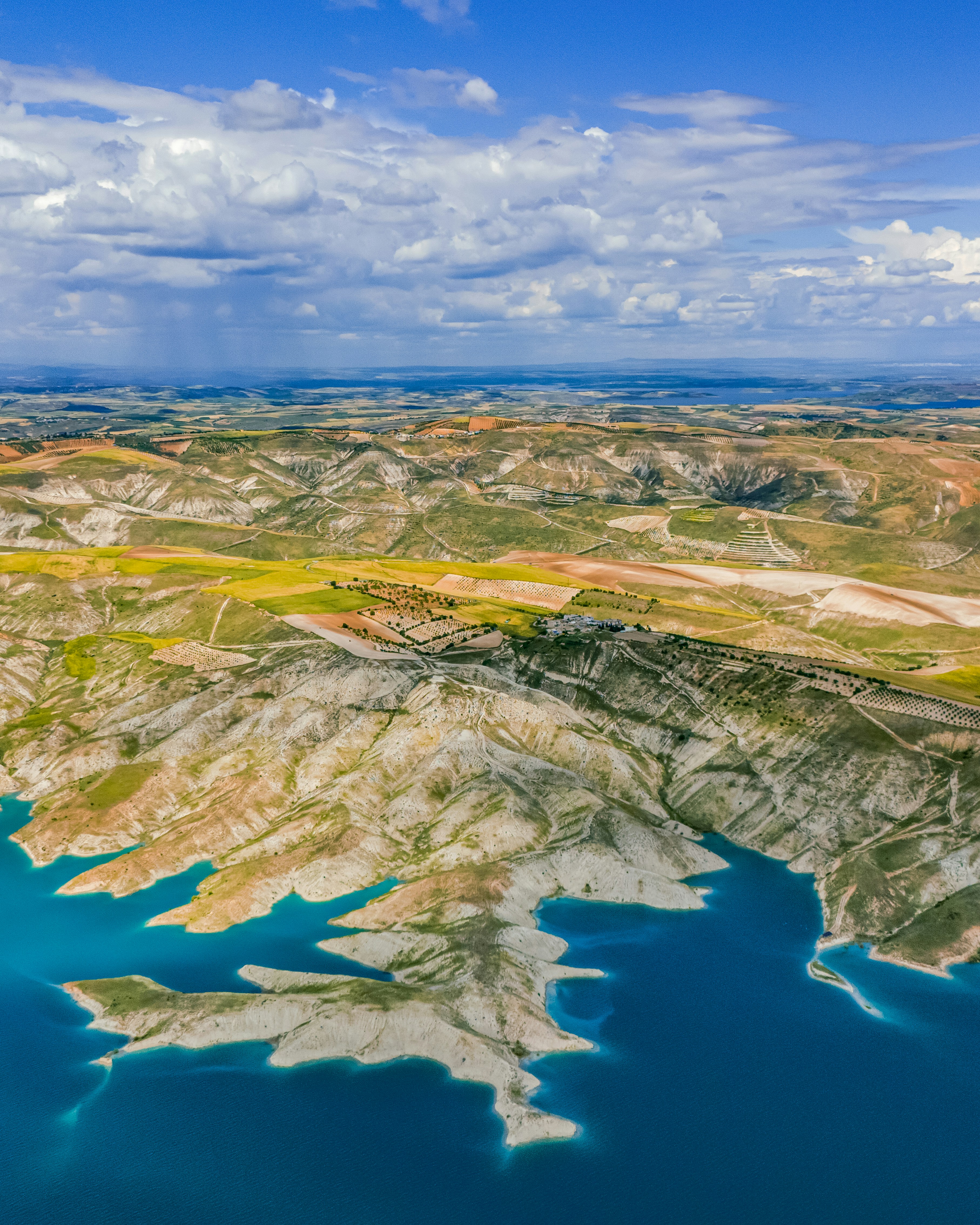 Aerial Palette Over the Rift: Terraced Hills Meeting Cerulean Waters