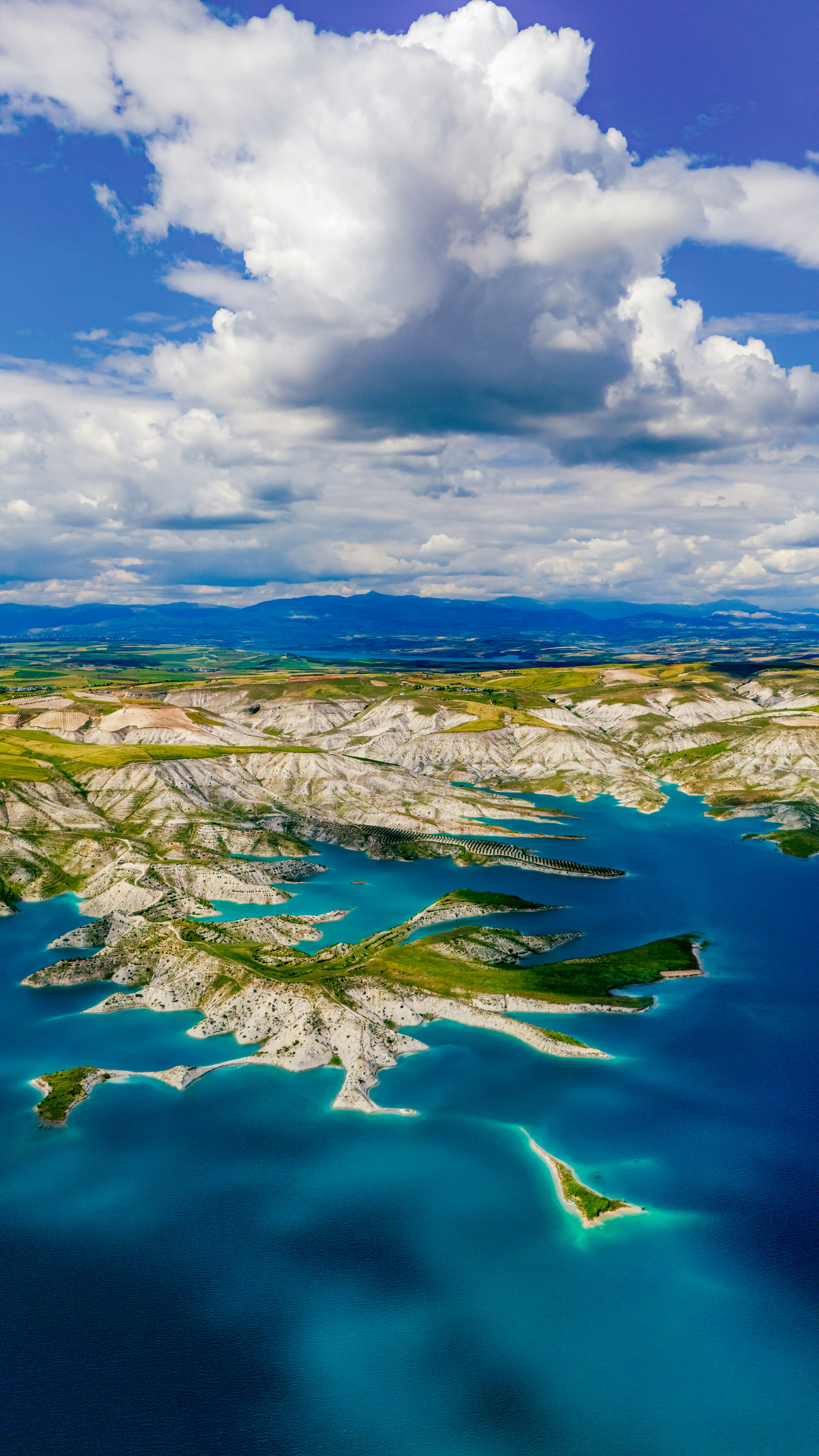 Aerial Rift: turquoise waterways weave through chalk-white cliffs under a looming cloudscape