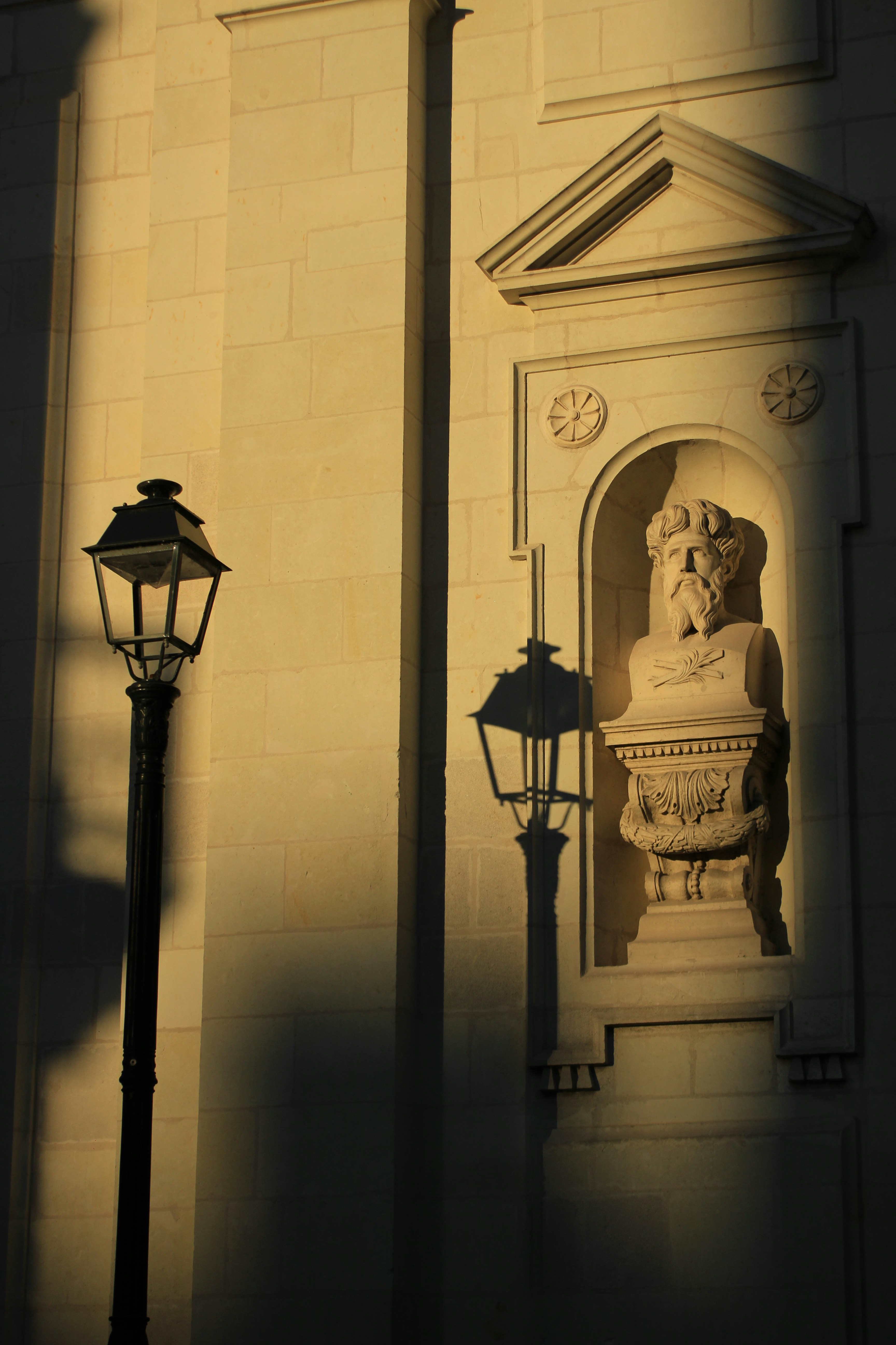Golden Hour Facade: Shadows and Statues on a Classical Wall