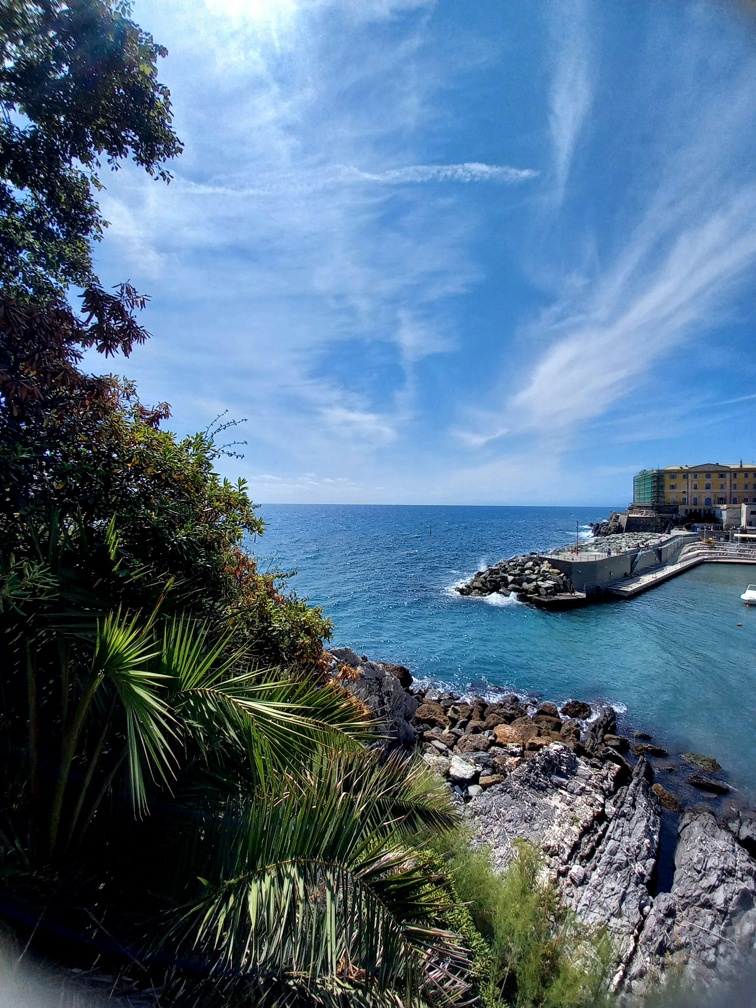 Harbor Edge: Sunlit Rocks and Blue Expanse
