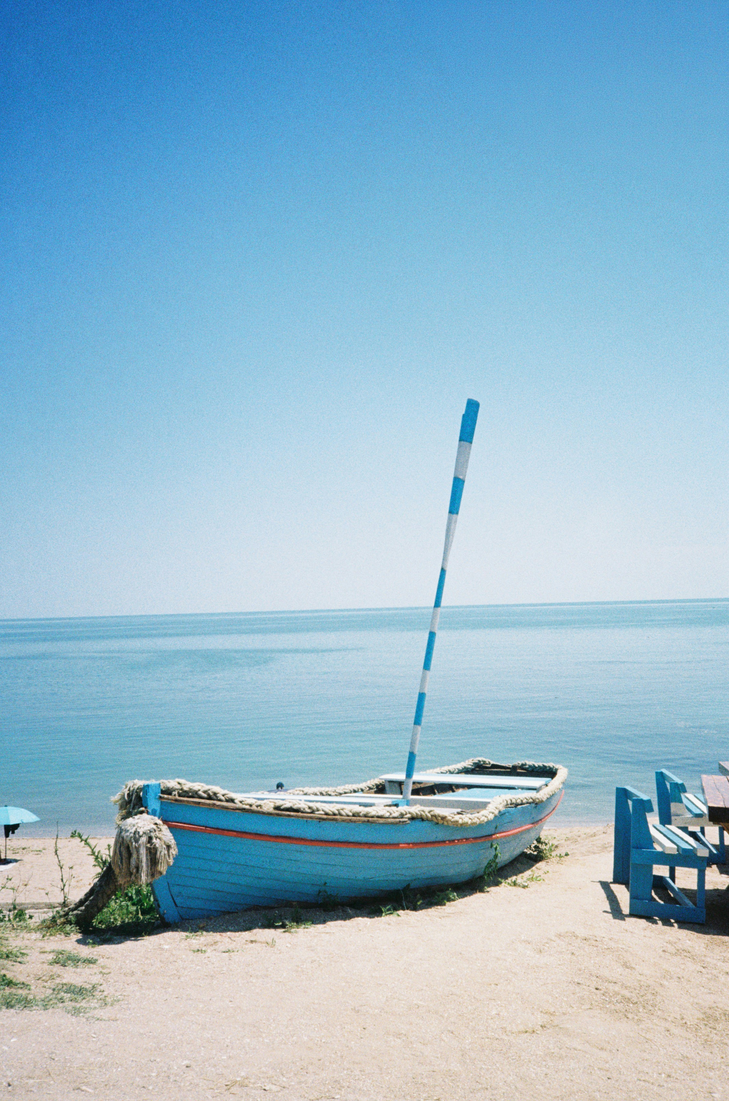 Blue Boat at Distant Shore under a Clear Coastal Sky