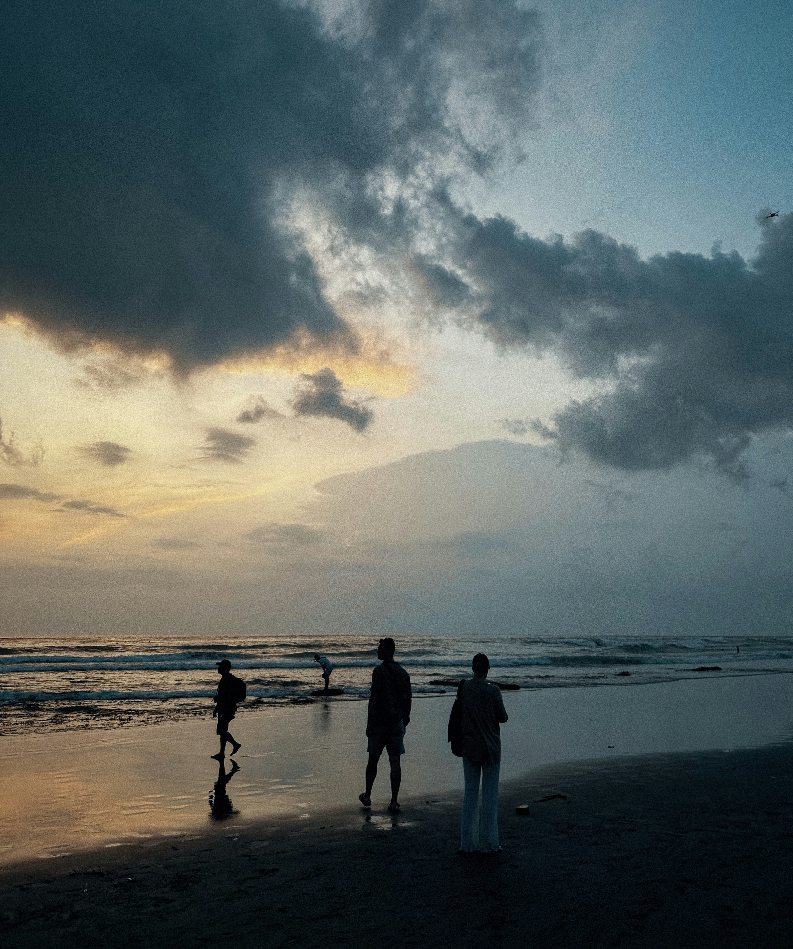 Silhouetted figures at dusk on a tranquil shoreline