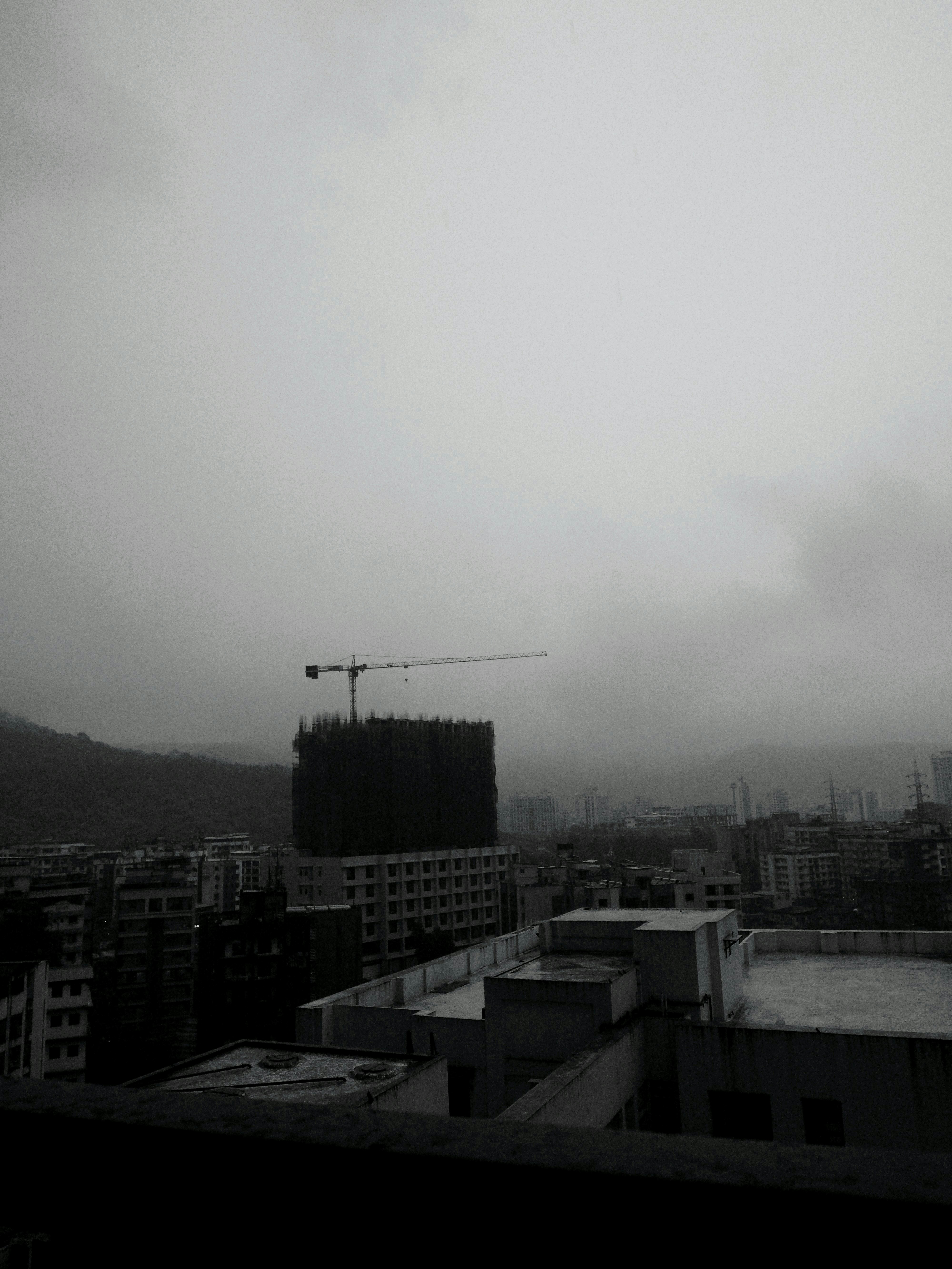 Midday Mist Over the City: Crane silhouette against low clouds