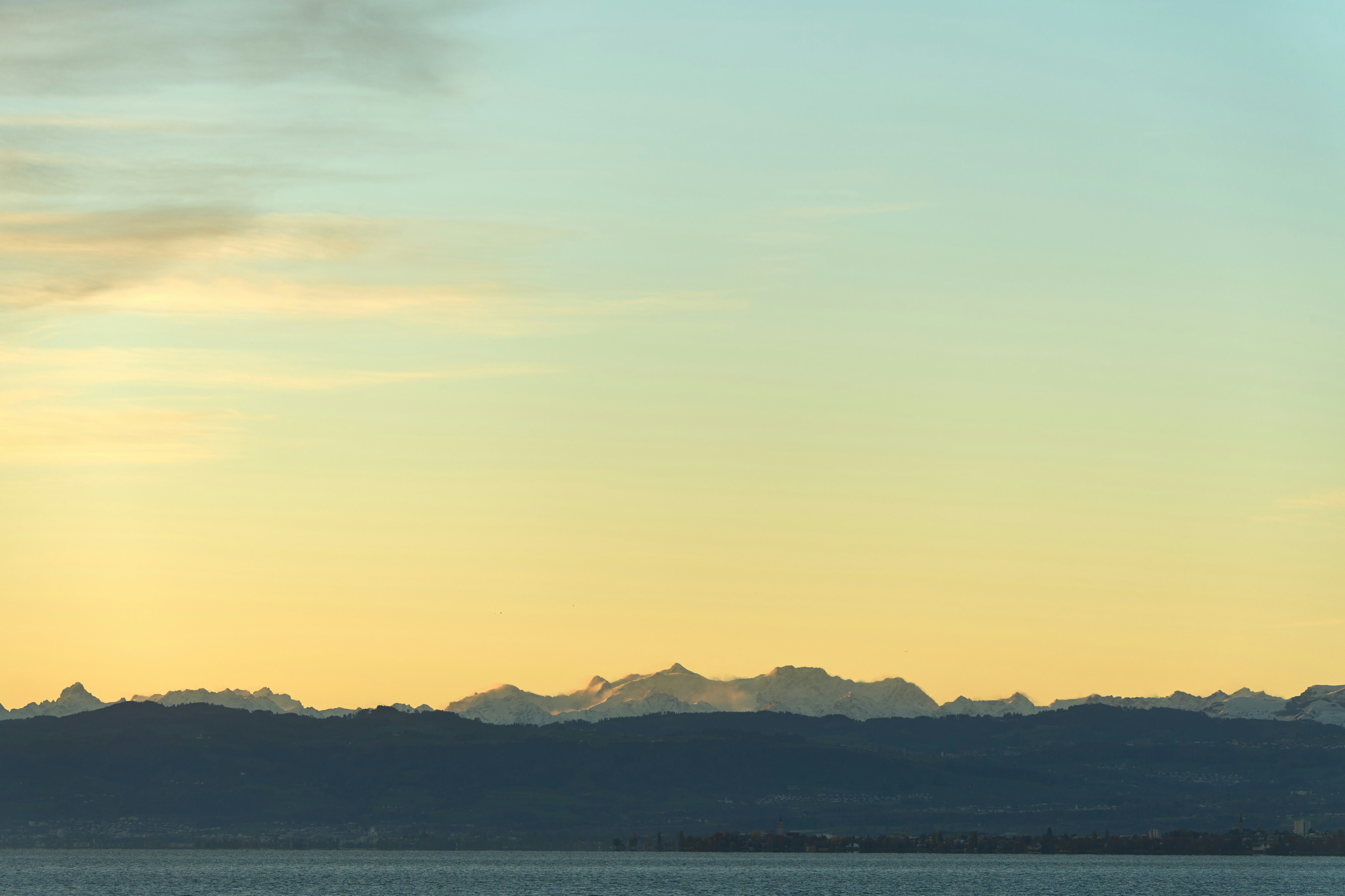 Quiet Horizon: Snow-capped Peaks Loom Above a Seabed Silhouette at Dusk