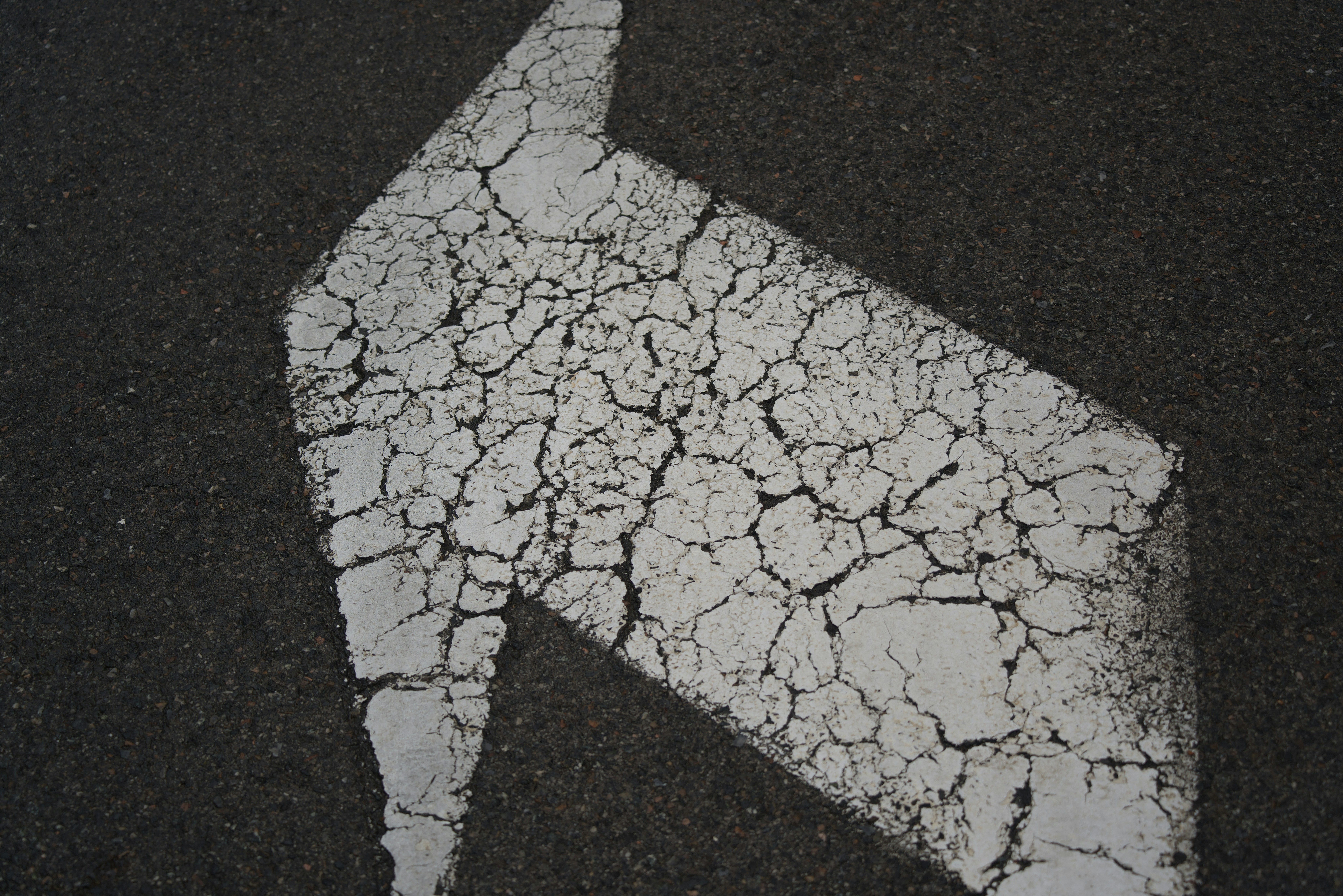 Cracked White Arrow: A Mark on Asphalt Guiding the Way