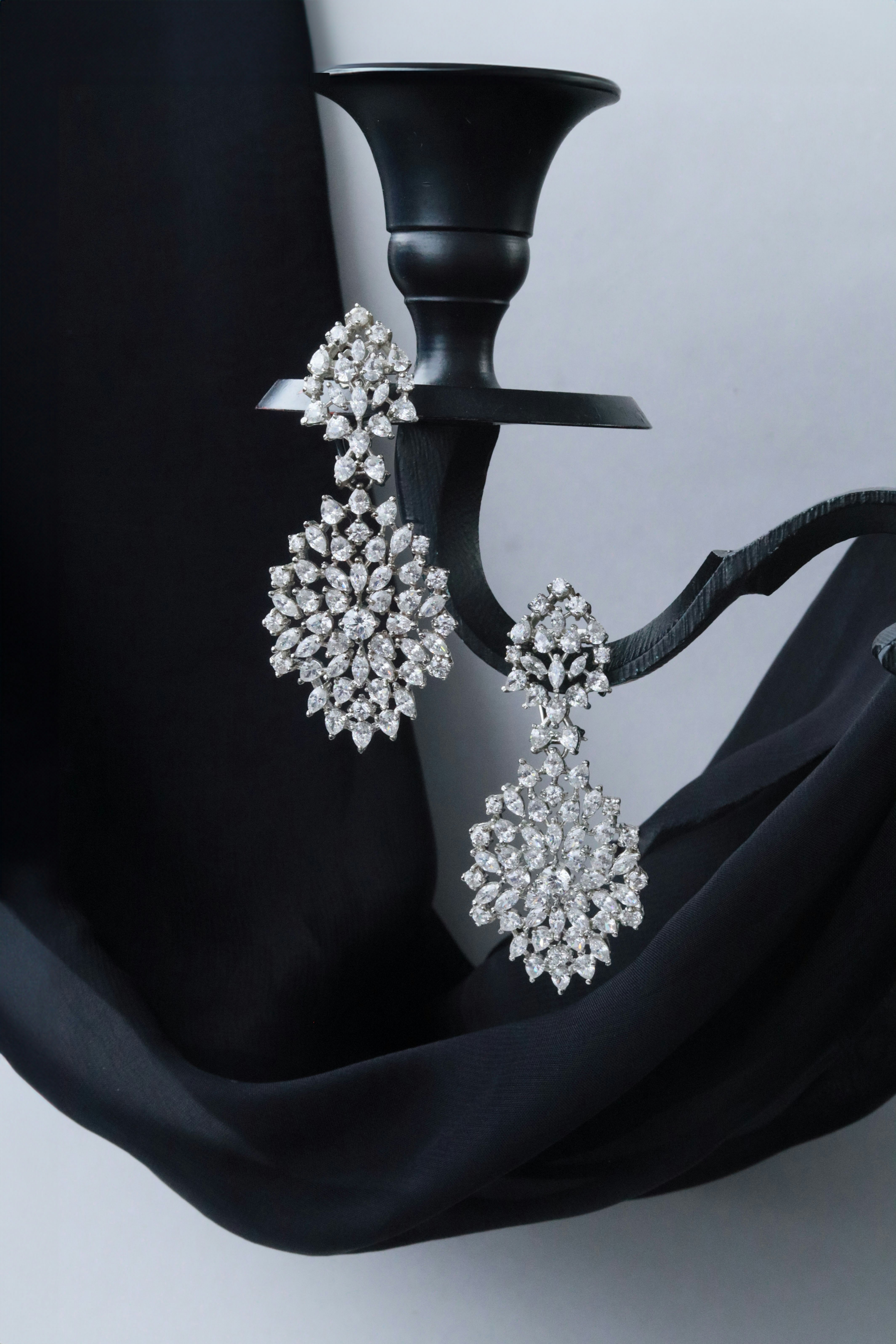 Dangling Diamond Lattice Earrings Draped Over a Matte Black Lamp