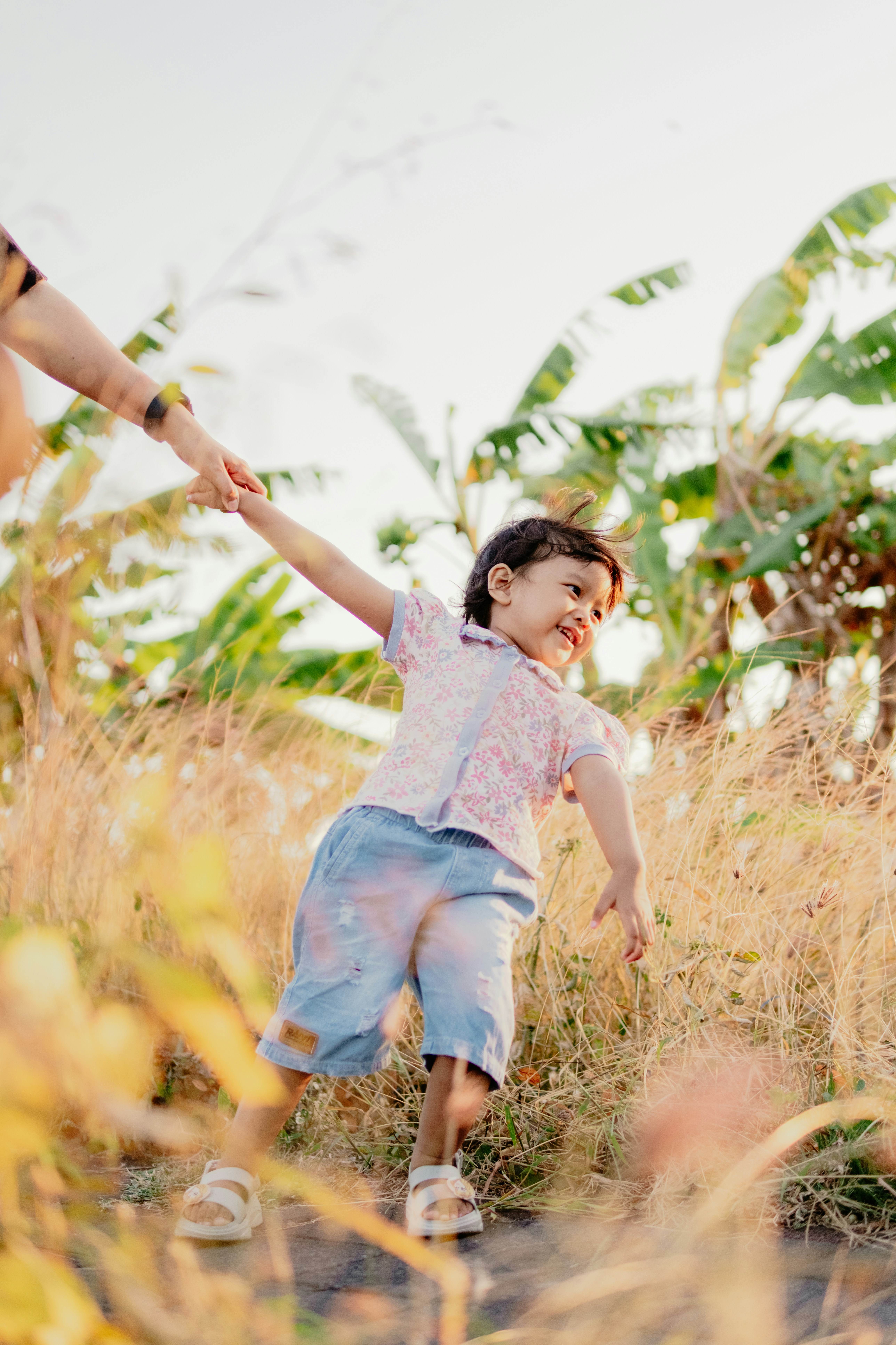 Holding Hands: A Joyful Leap Through Sunny Grass