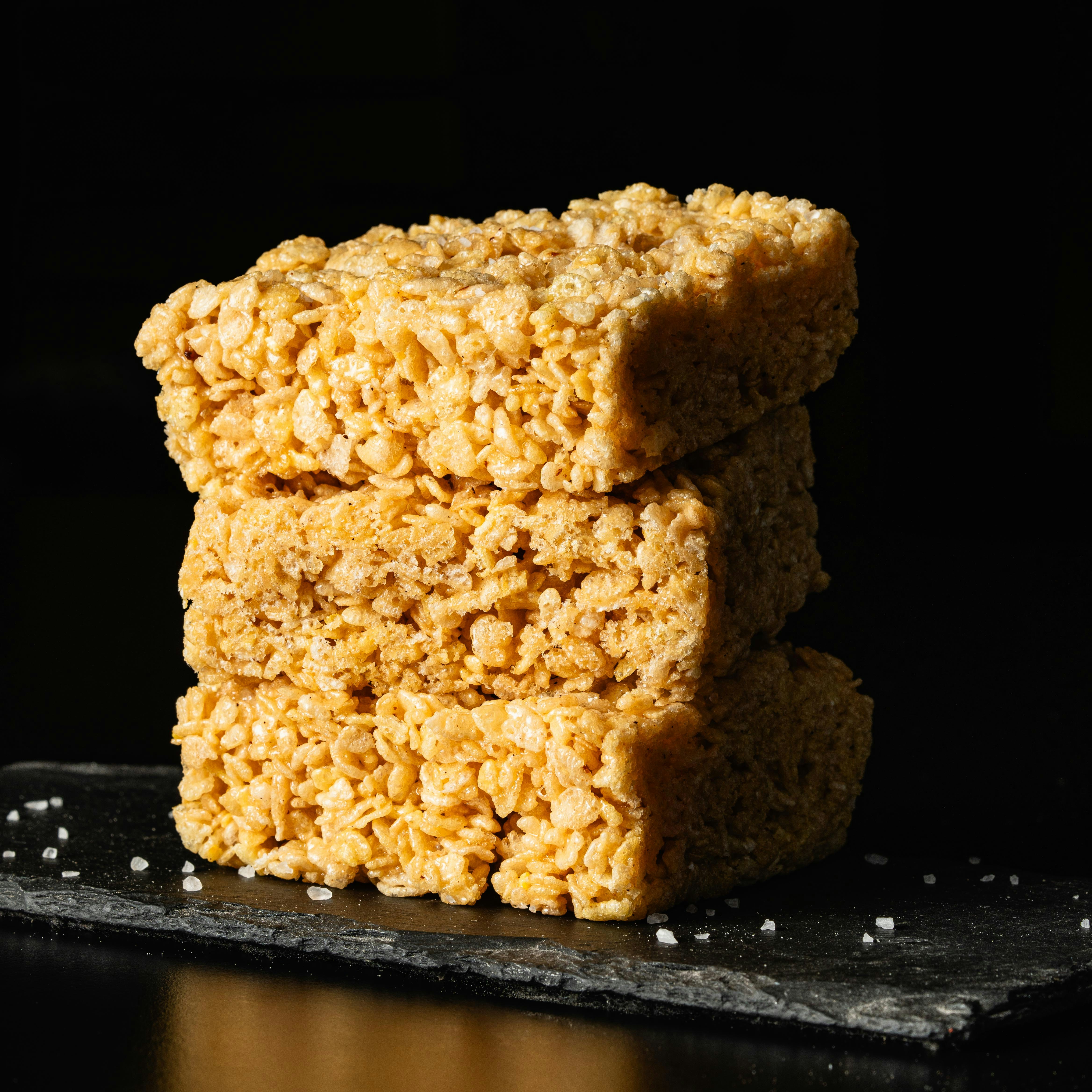 Stacked Crunch: Golden Rice Krispie Treats on a Dark Slate