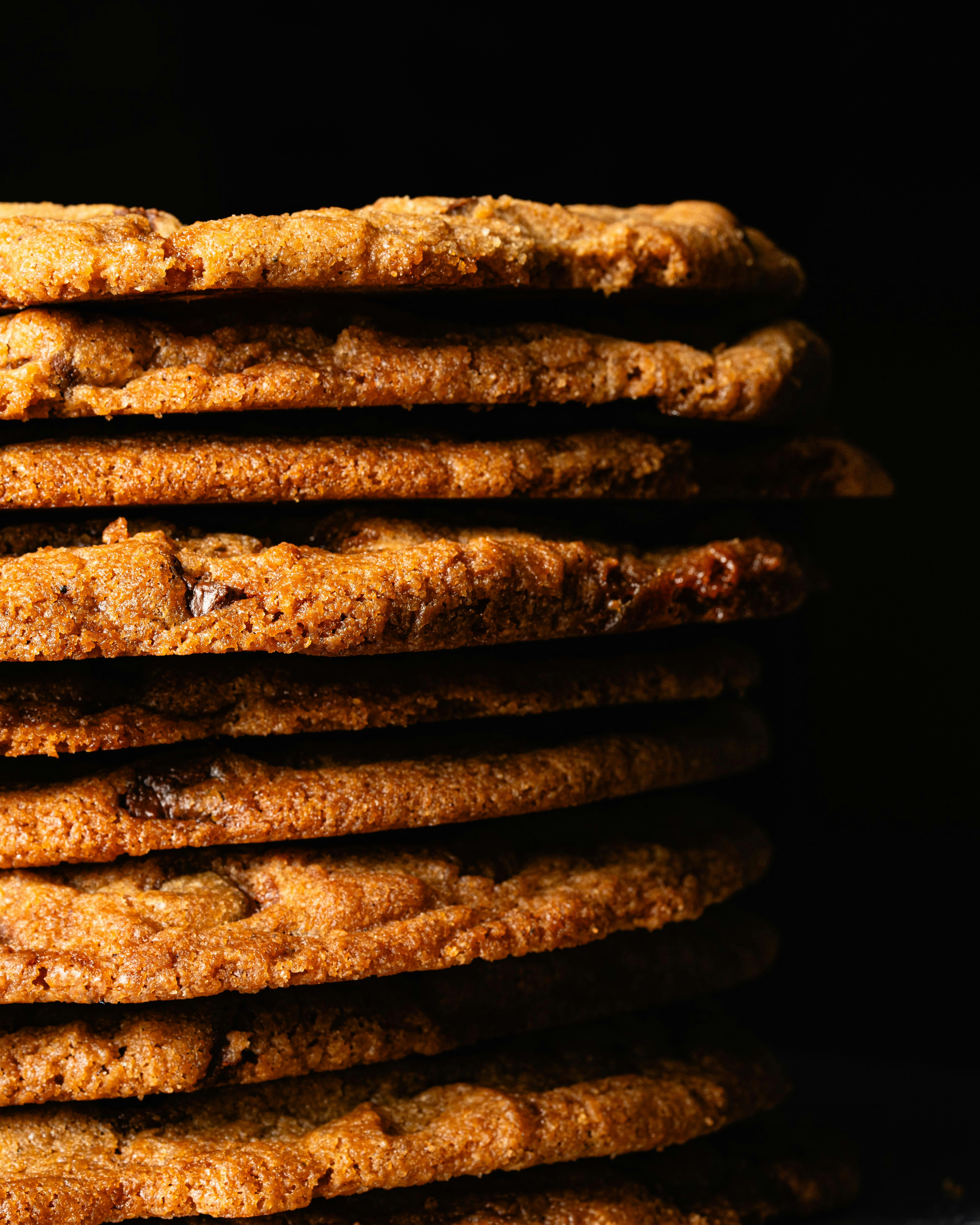 Stacked Crunch: A Close-Up of Golden Cookies Resting Against Velvet Darkness