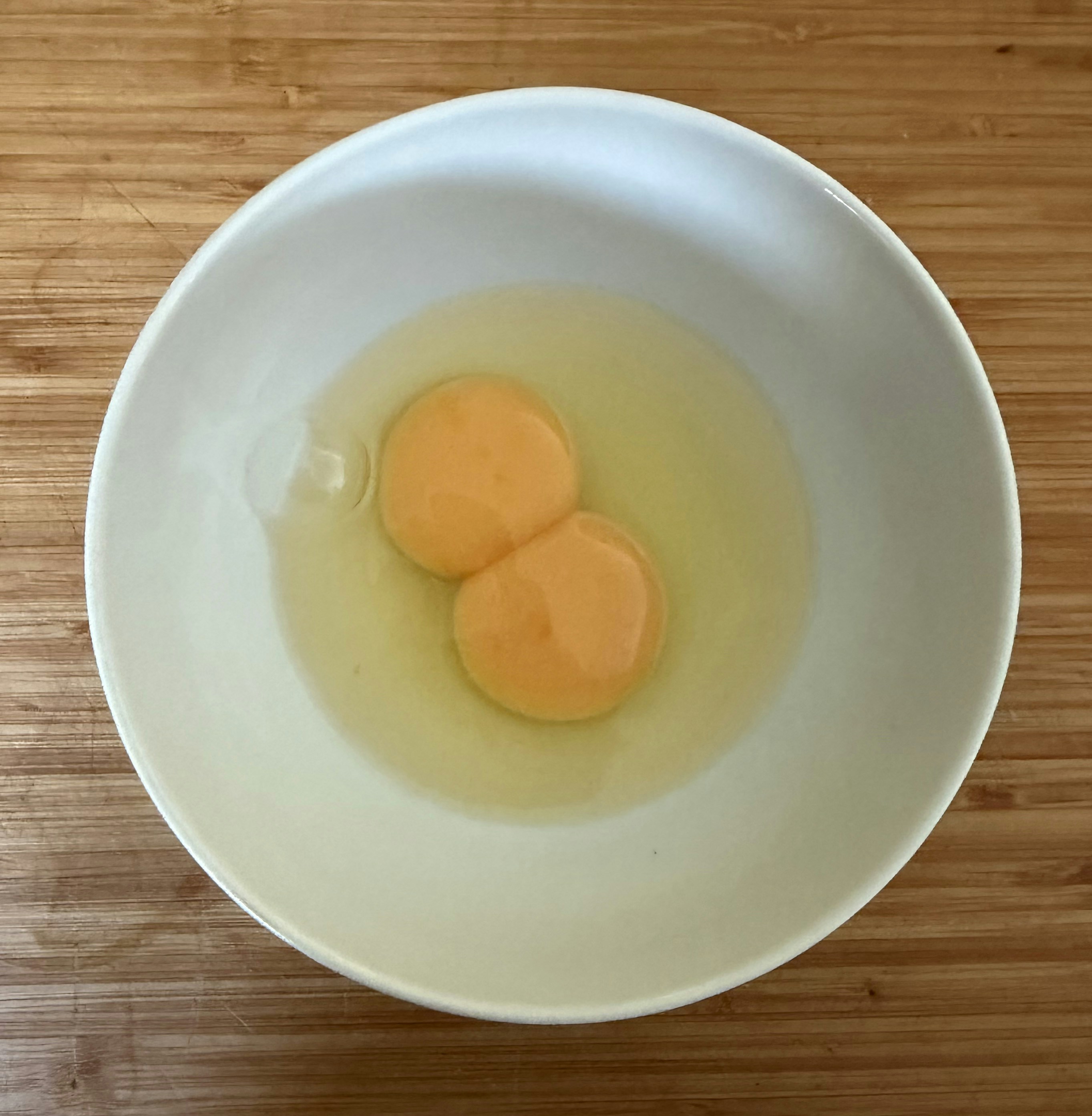 Two sunny eggs in a pale bowl—simple breakfast quiet