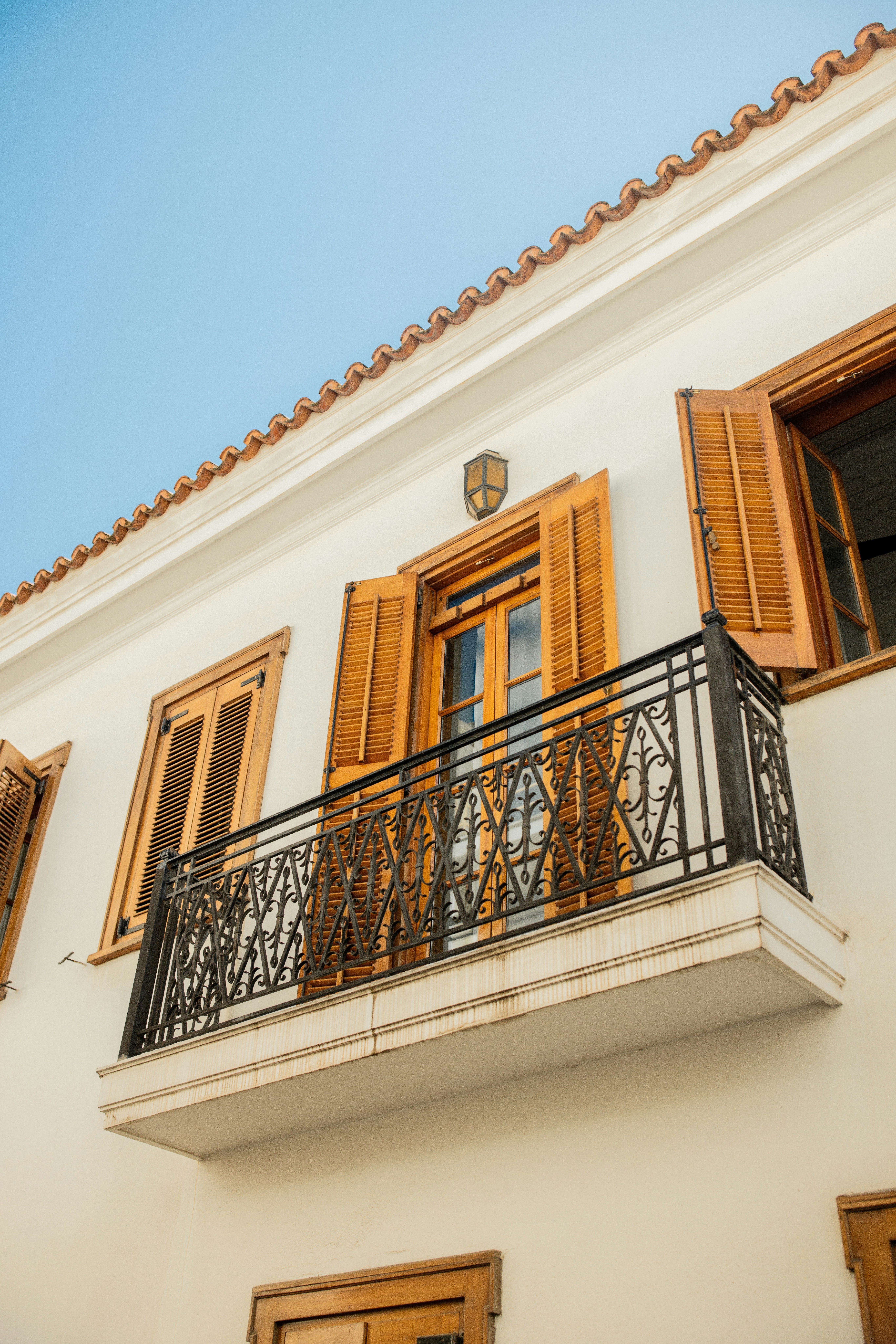 Sunlit Balcony with Wooden Shutters on a Mediterranean Facade