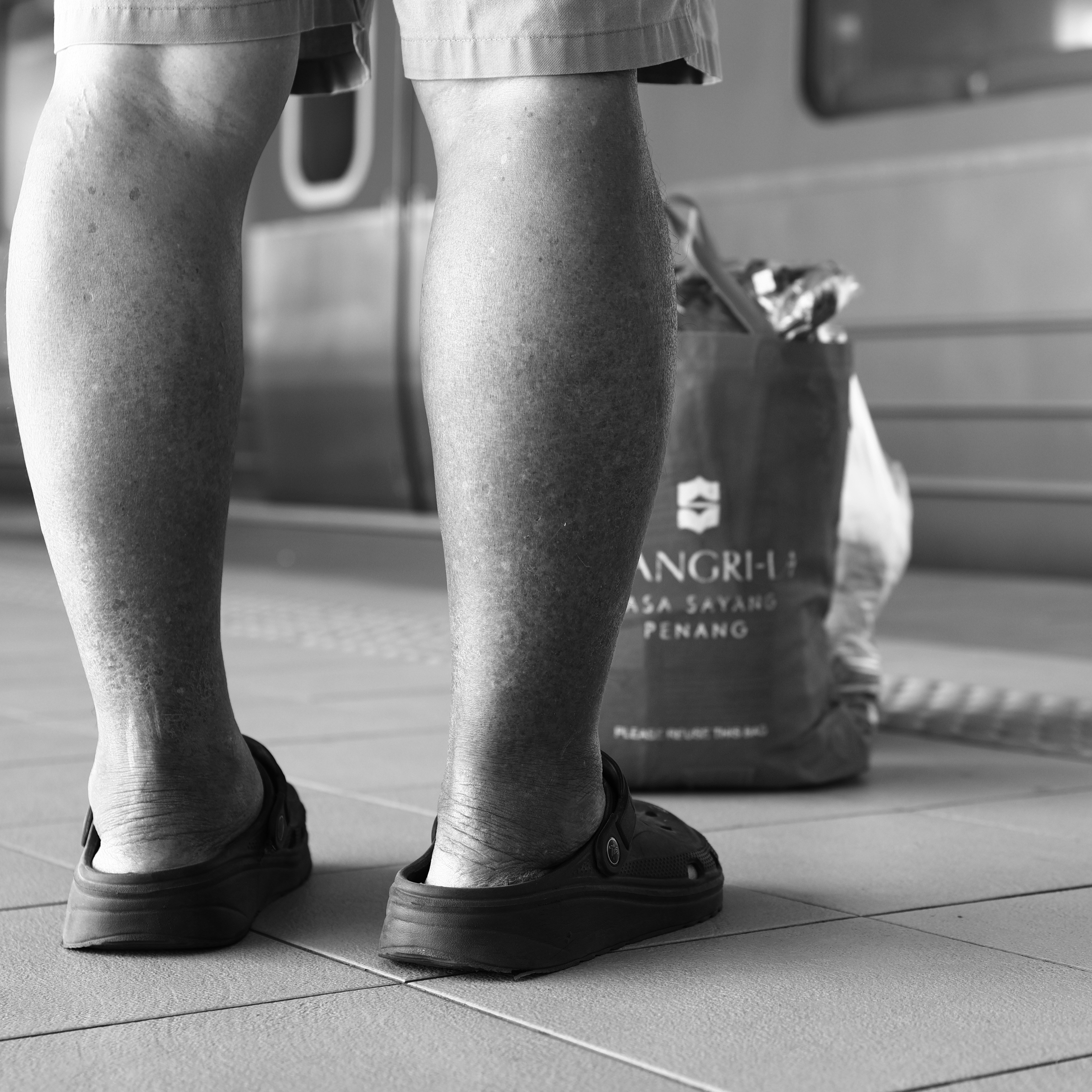 Lower Legs at the Bus Stop: A Quiet Moment by the Train