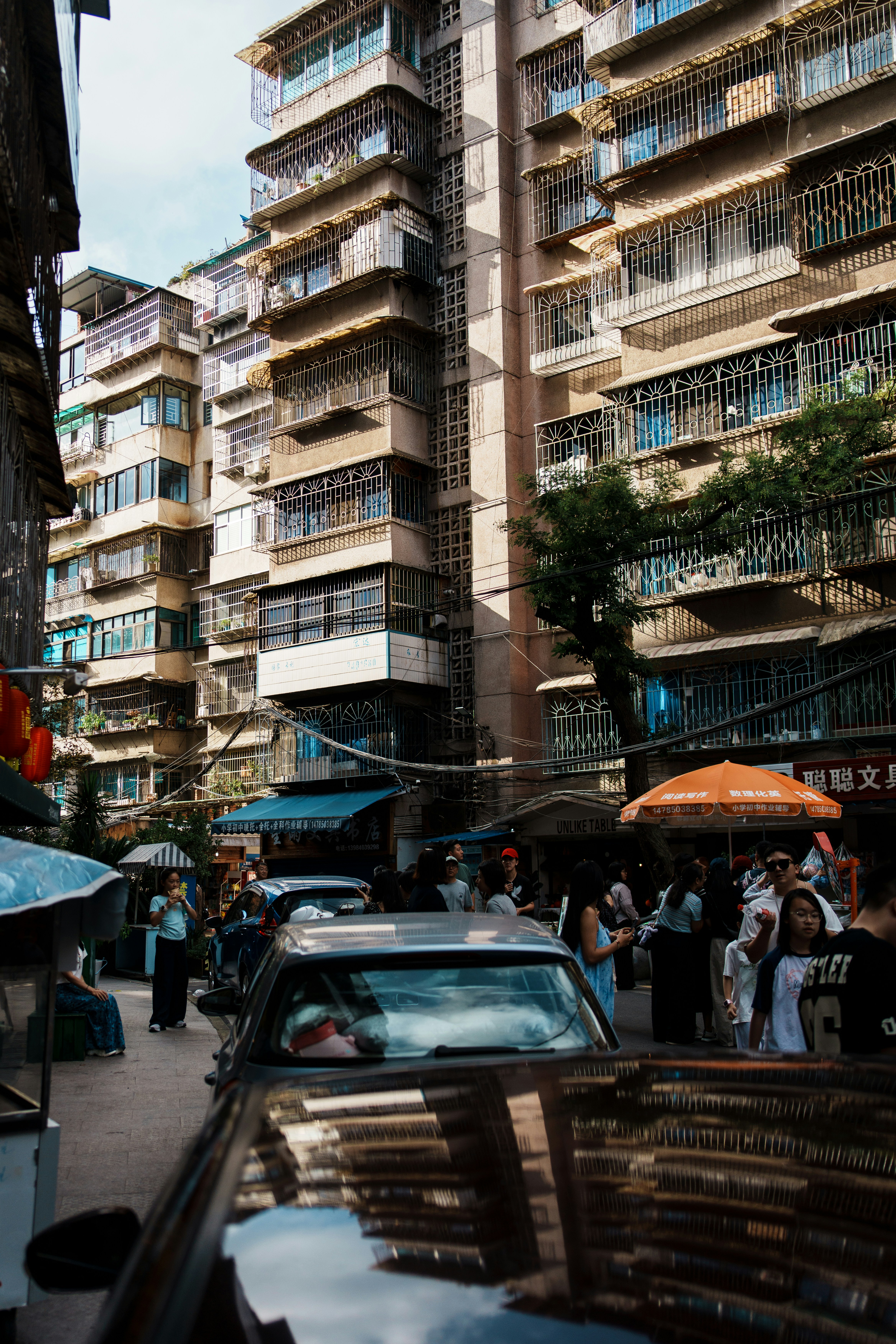 Urban Corridor: Cars, Crowds, and Balconies in a Sunlit Alley