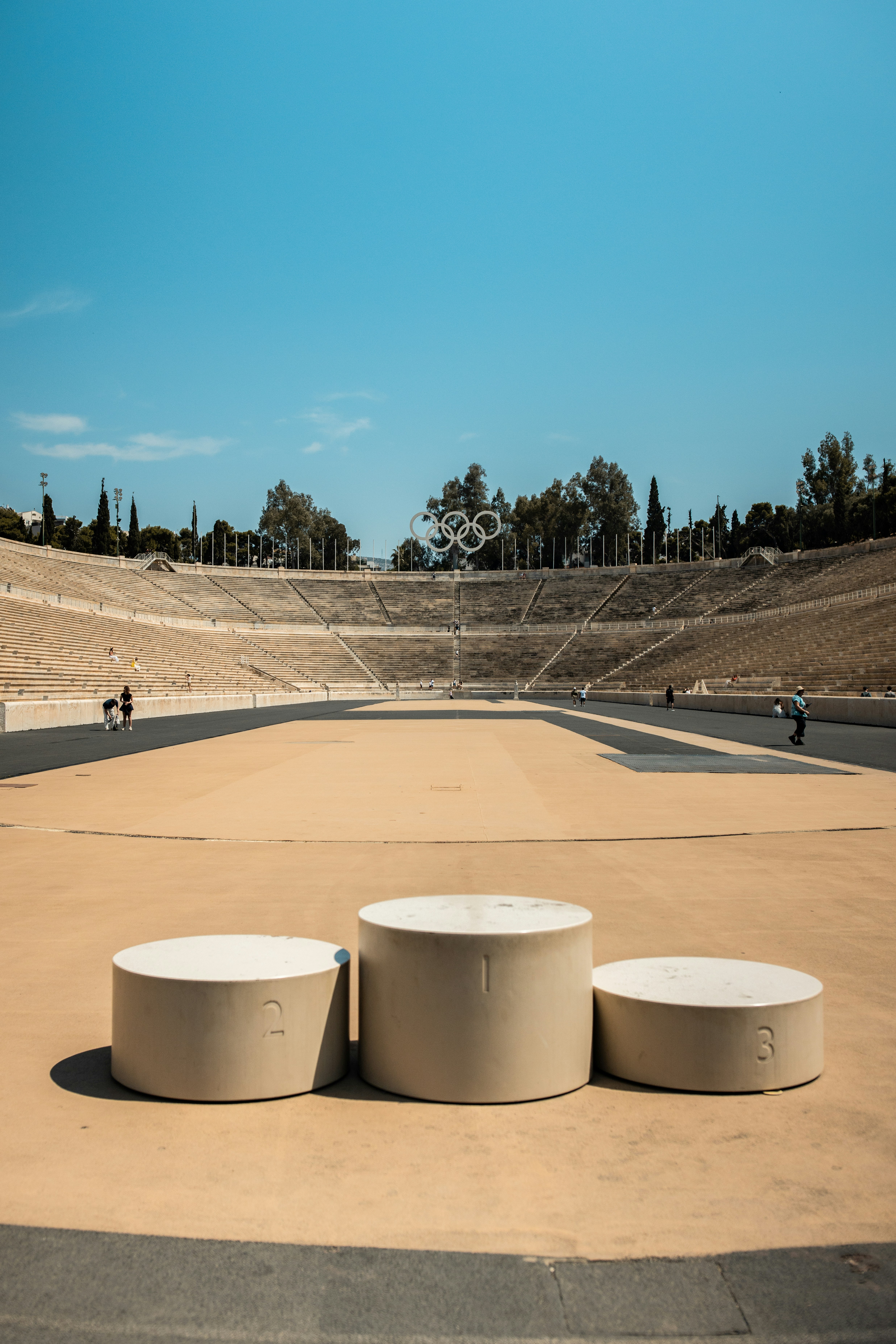 Three Pedestals in a Silent Arena Under an Olympic Sky