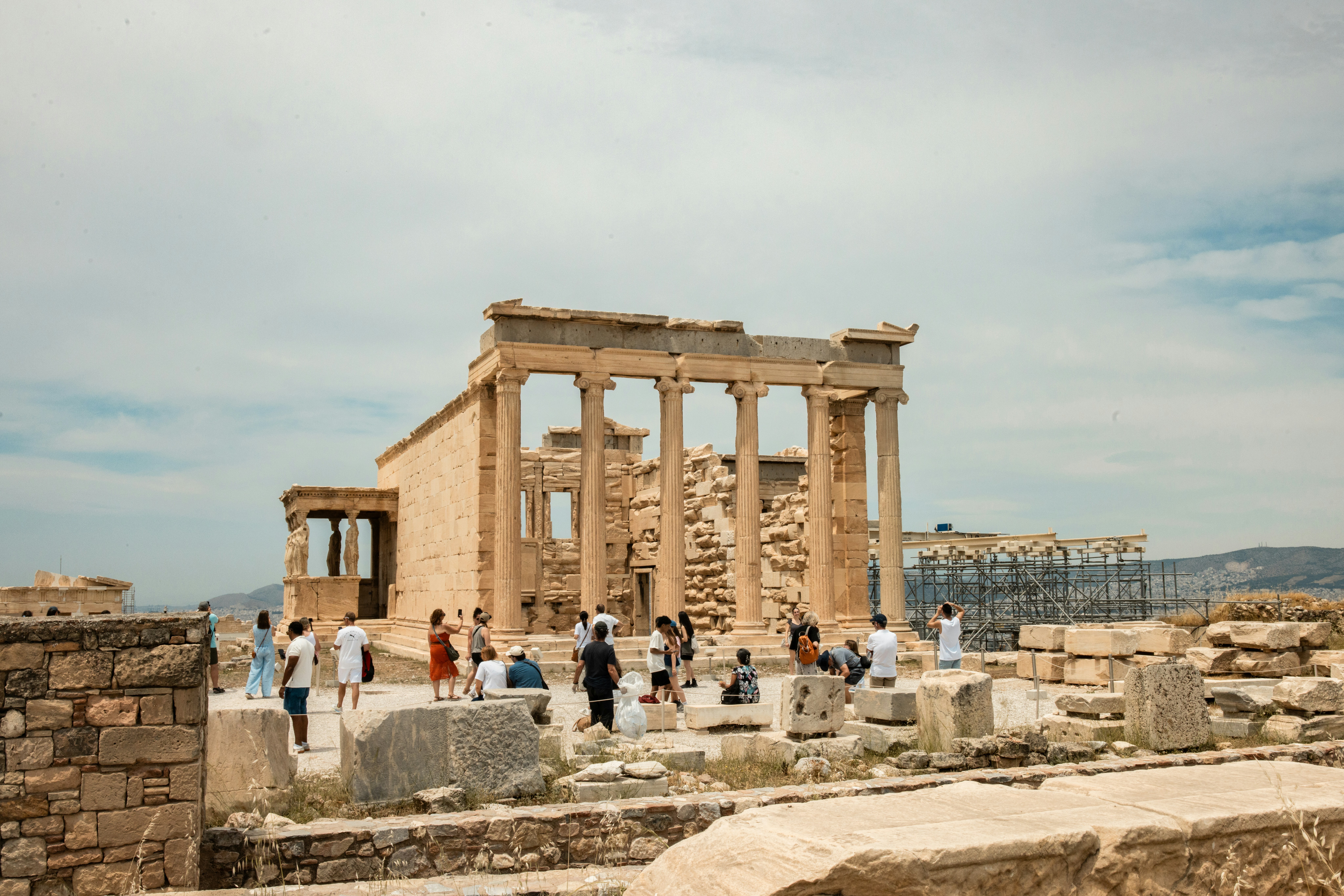 Columns of Antiquity: Visitors Explore the Ruins of a Grecian Temple Against a Seaside Sky