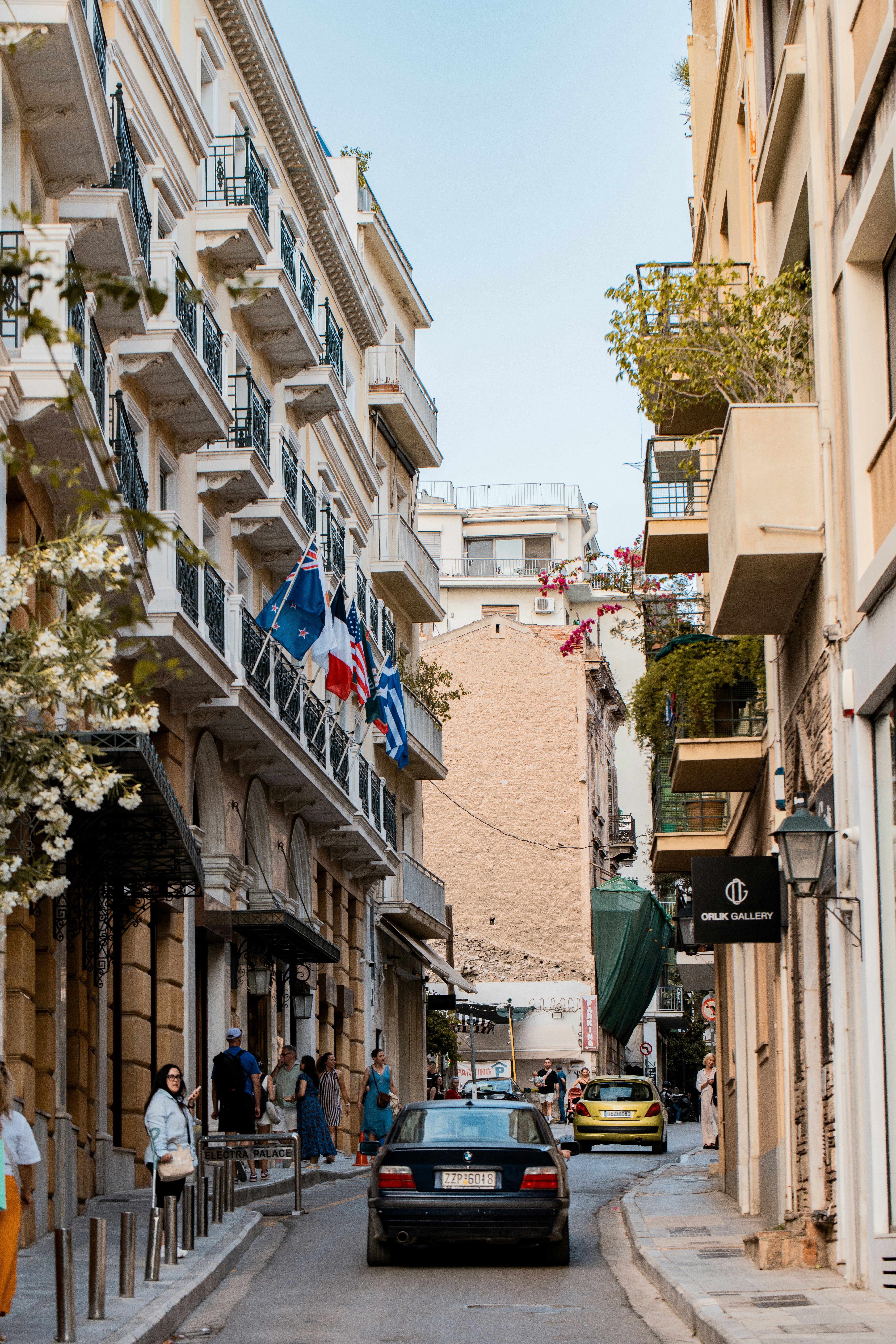 Cobbled Street Portrait: Cars and Cascading Facades in Warm Noon Light