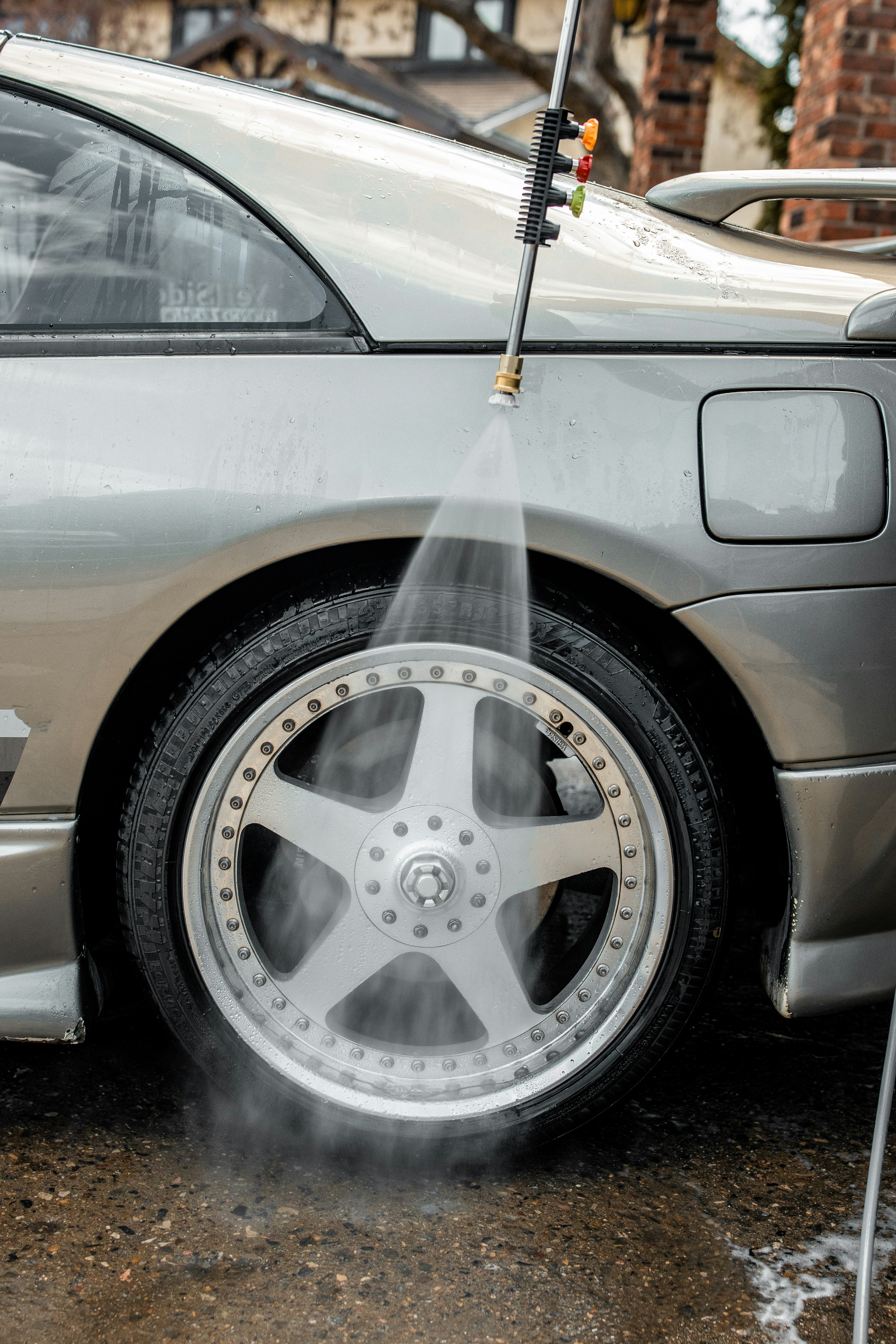 Jet of water over a silver alloy wheel during car wash