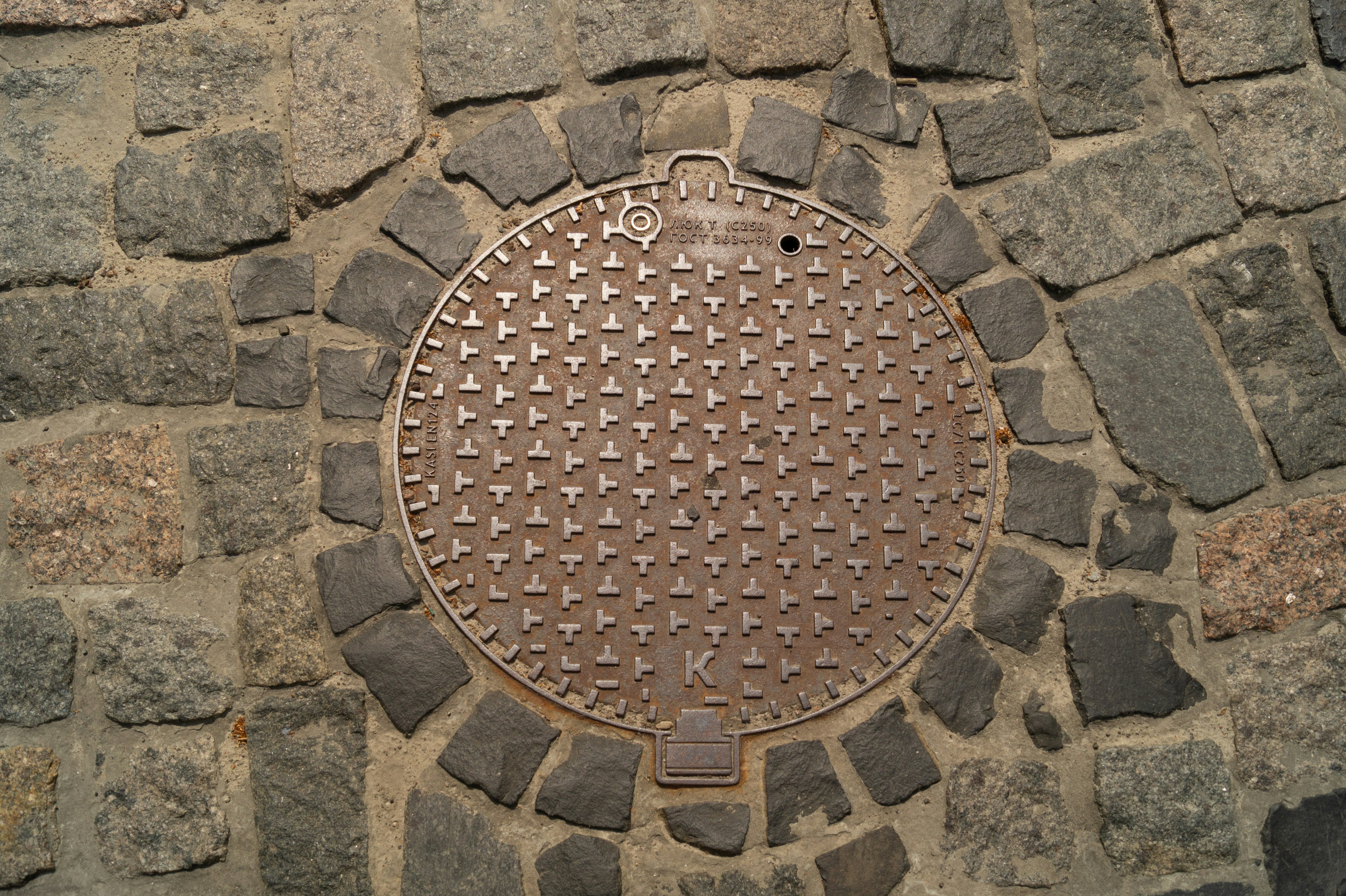 Iron Circle in a Stone Mosaic: A Close Look at a Manhole Cover