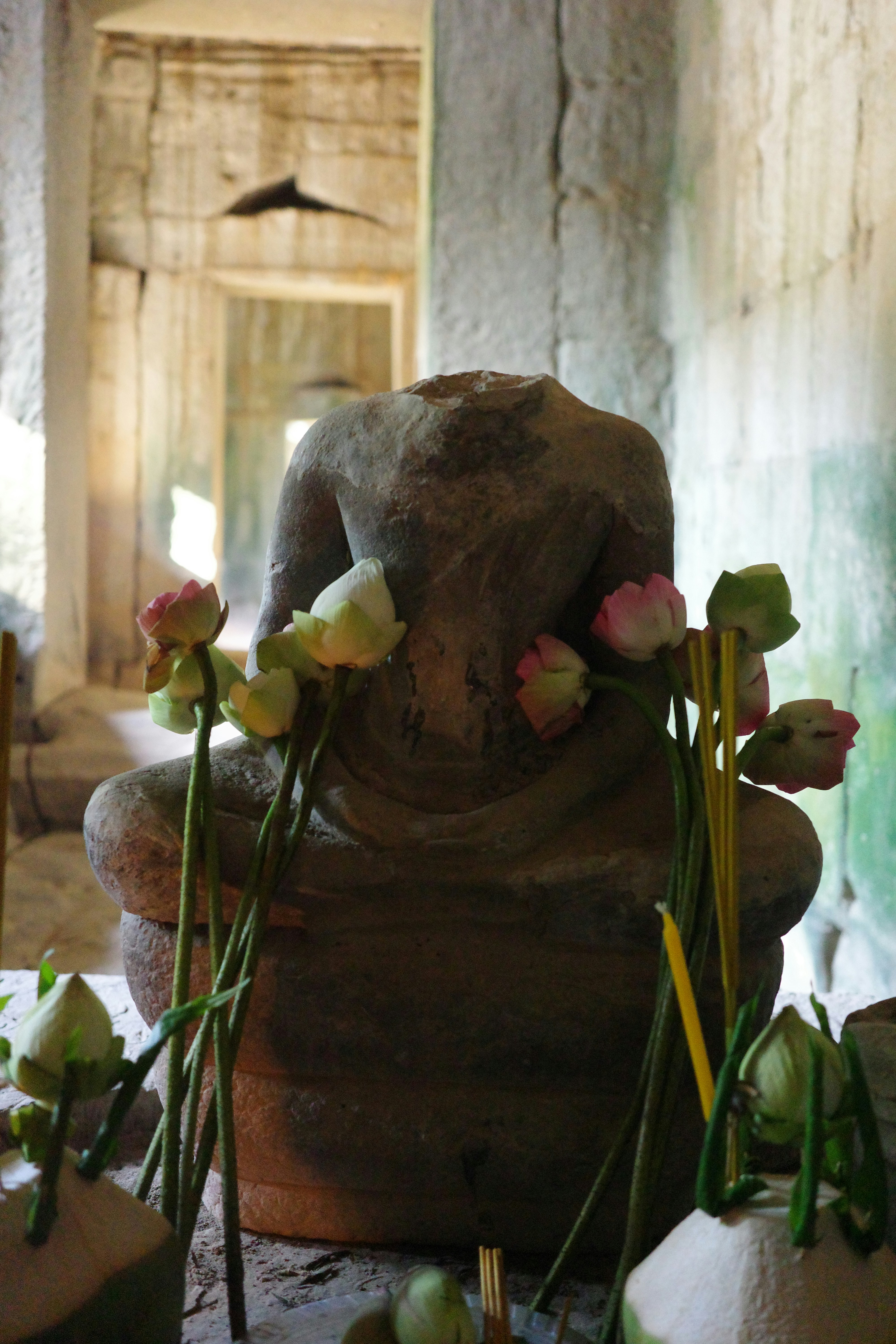 Headless buddha statue with lotus flowers in an ancient temple.