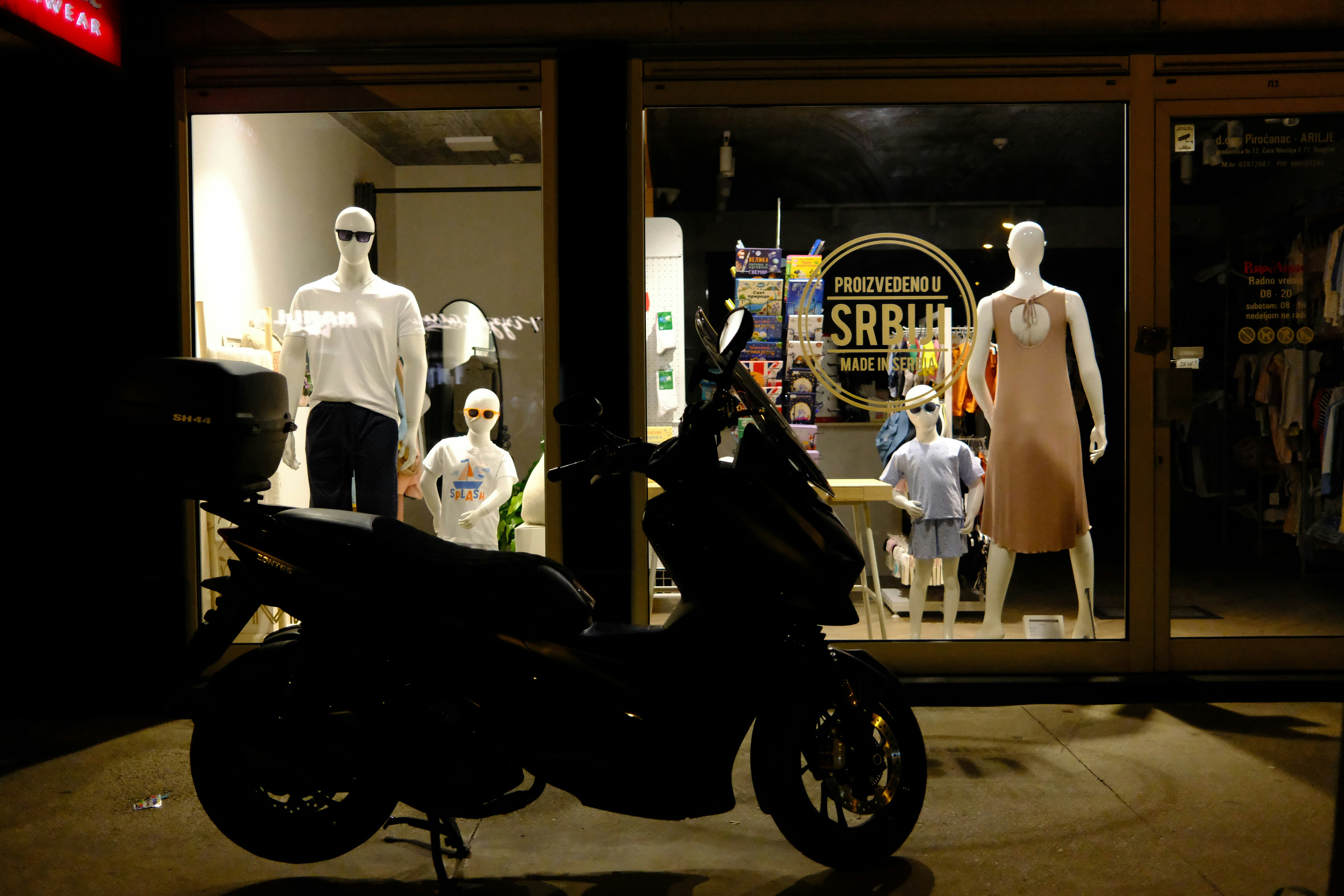 Night Window with Silhouettes: Mannequins and a Motorcycle in Front of a Boutique