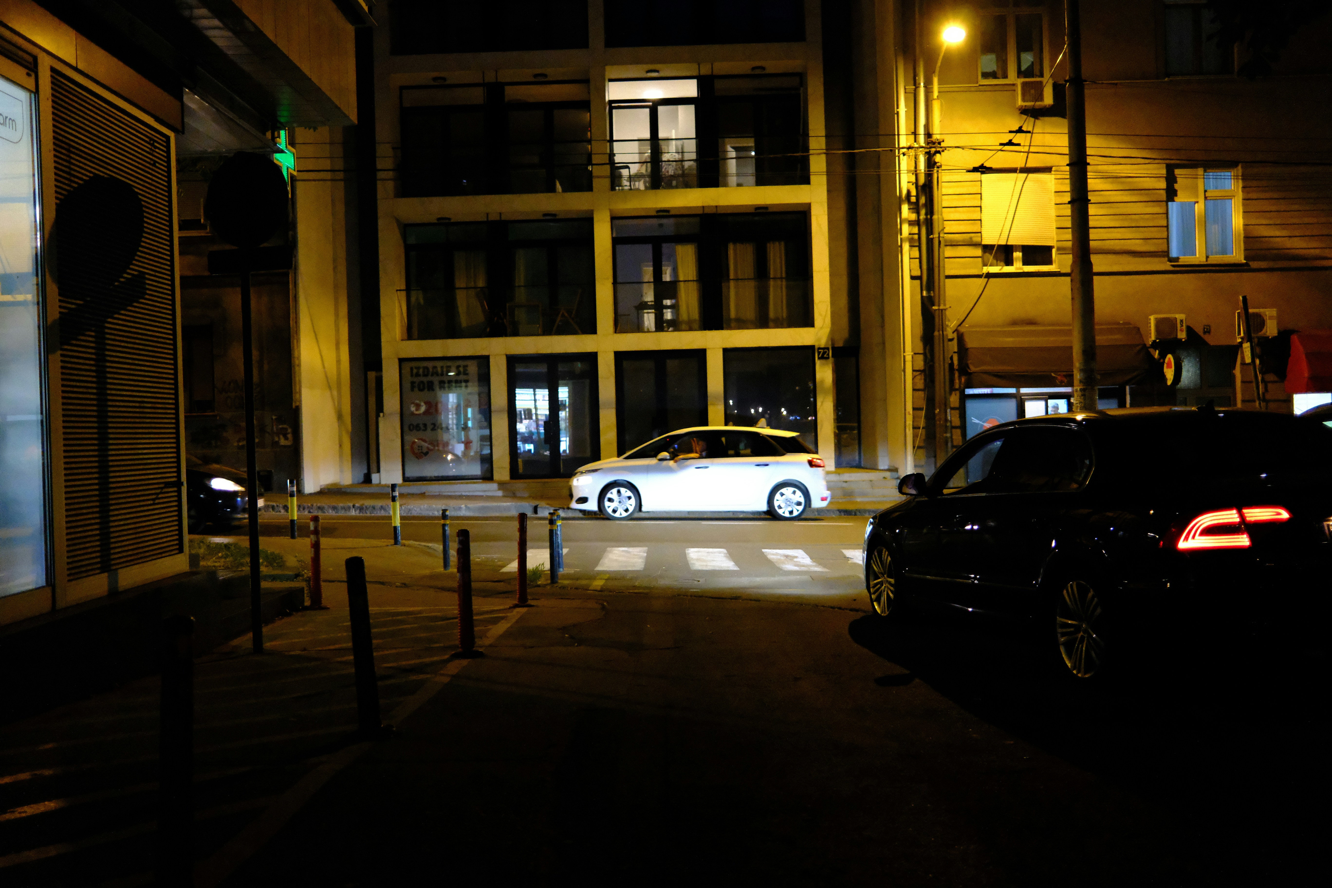 White sedan under streetlight glow anchors a quiet urban night
