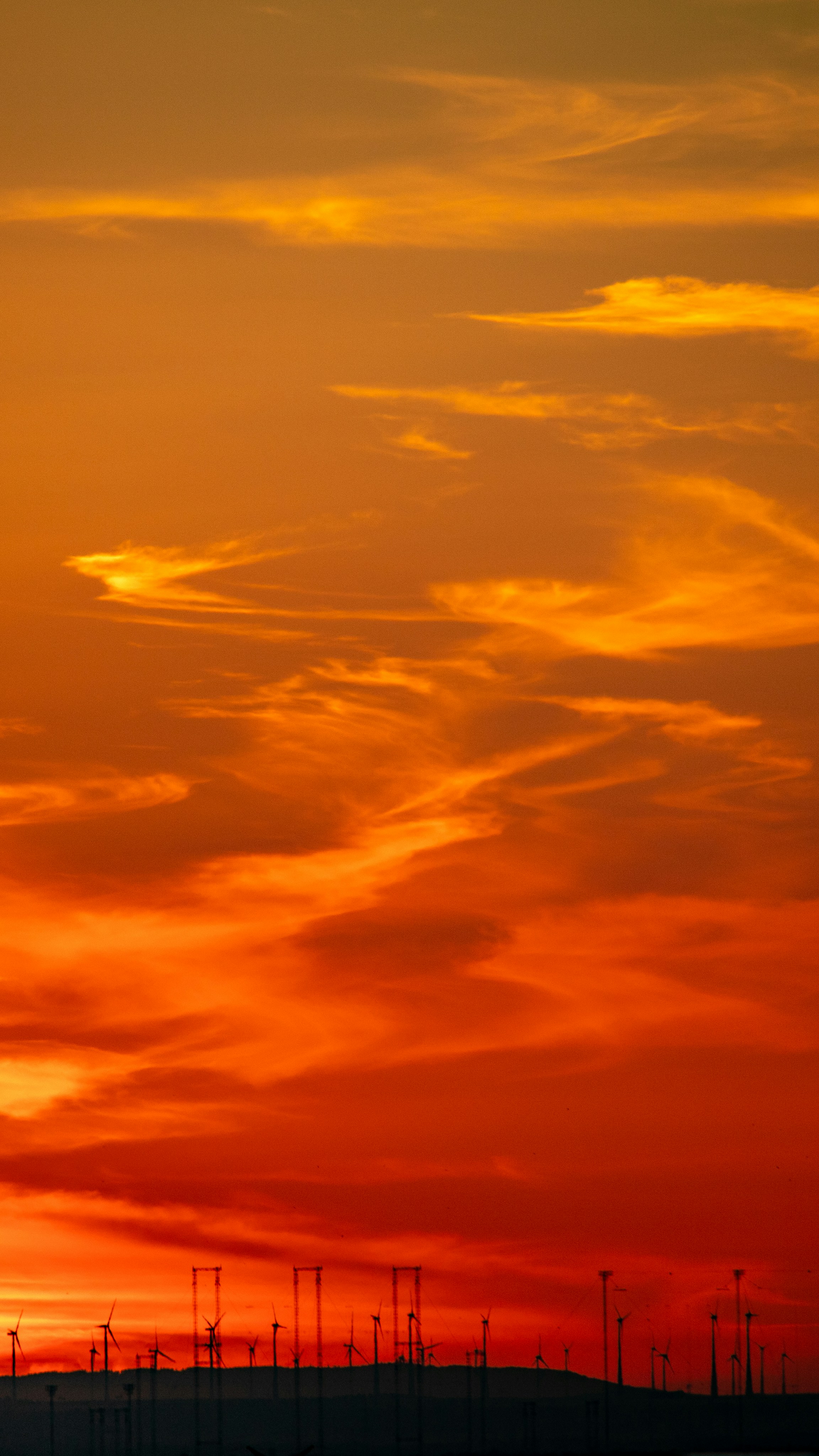 Steel silhouettes at dusk: a horizon of wind turbines under molten skies