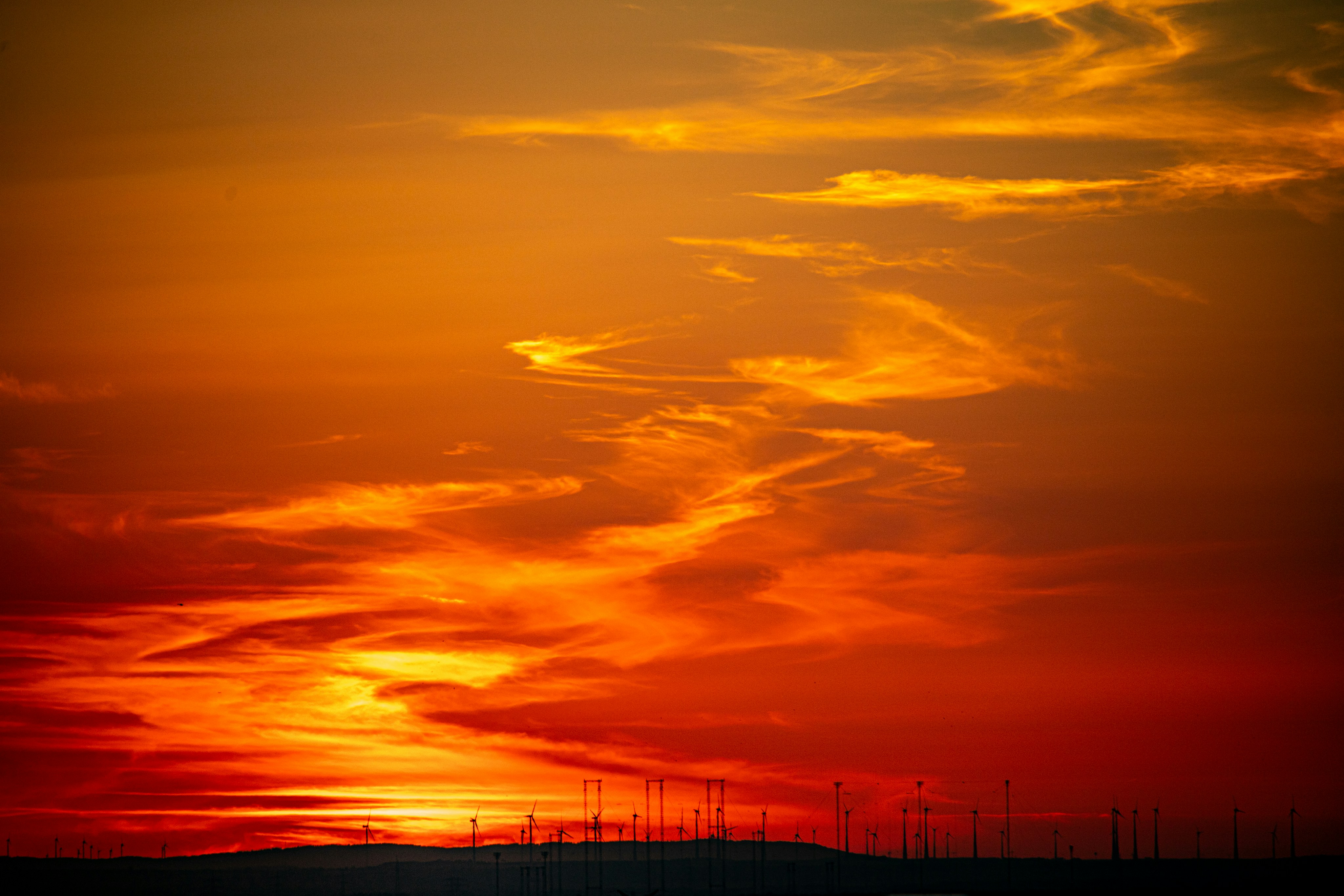 Ember Horizon: Fiery Sunset Over a Silhouetted Windscape
