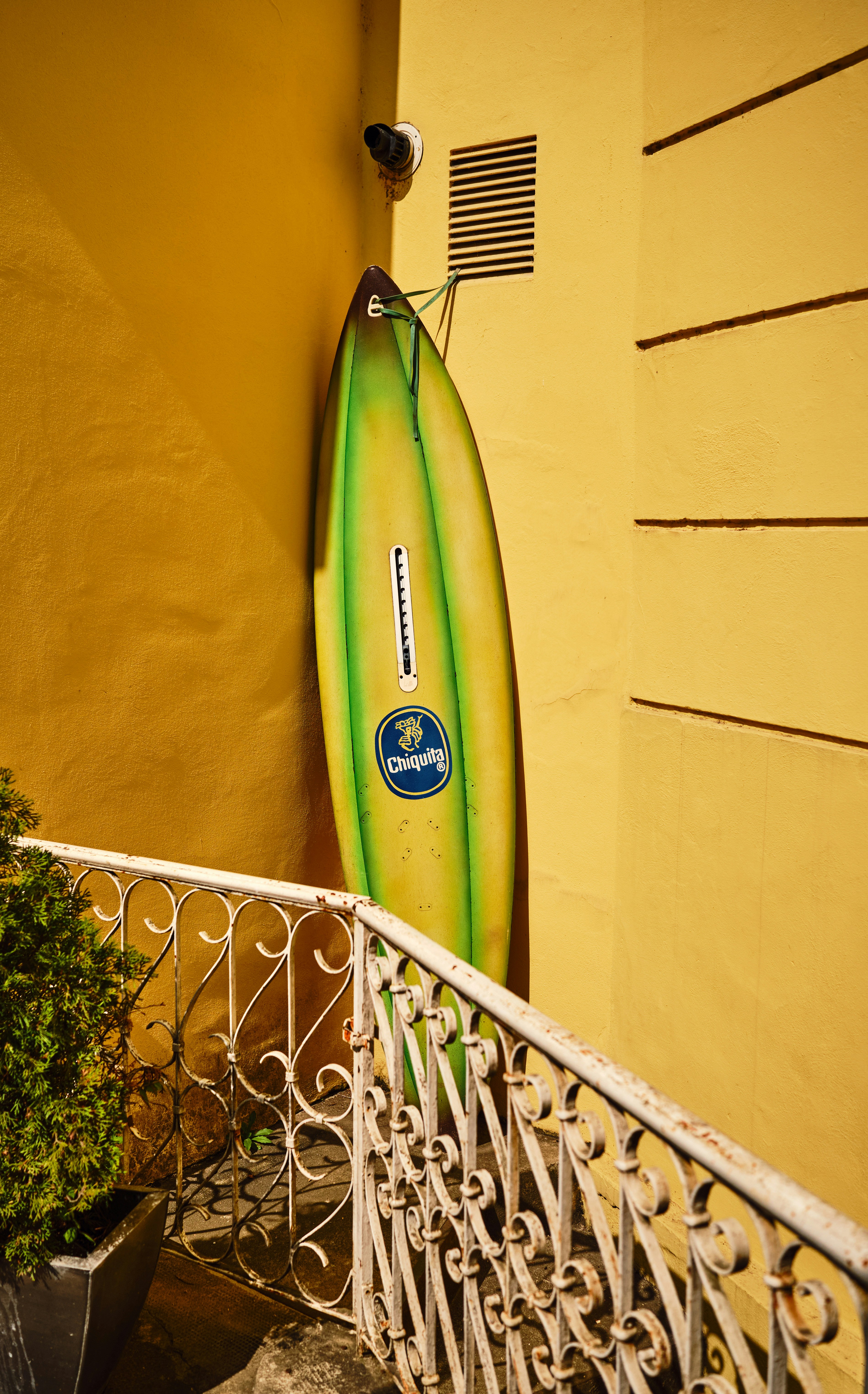 Surfboard in a sunlit yellow courtyard