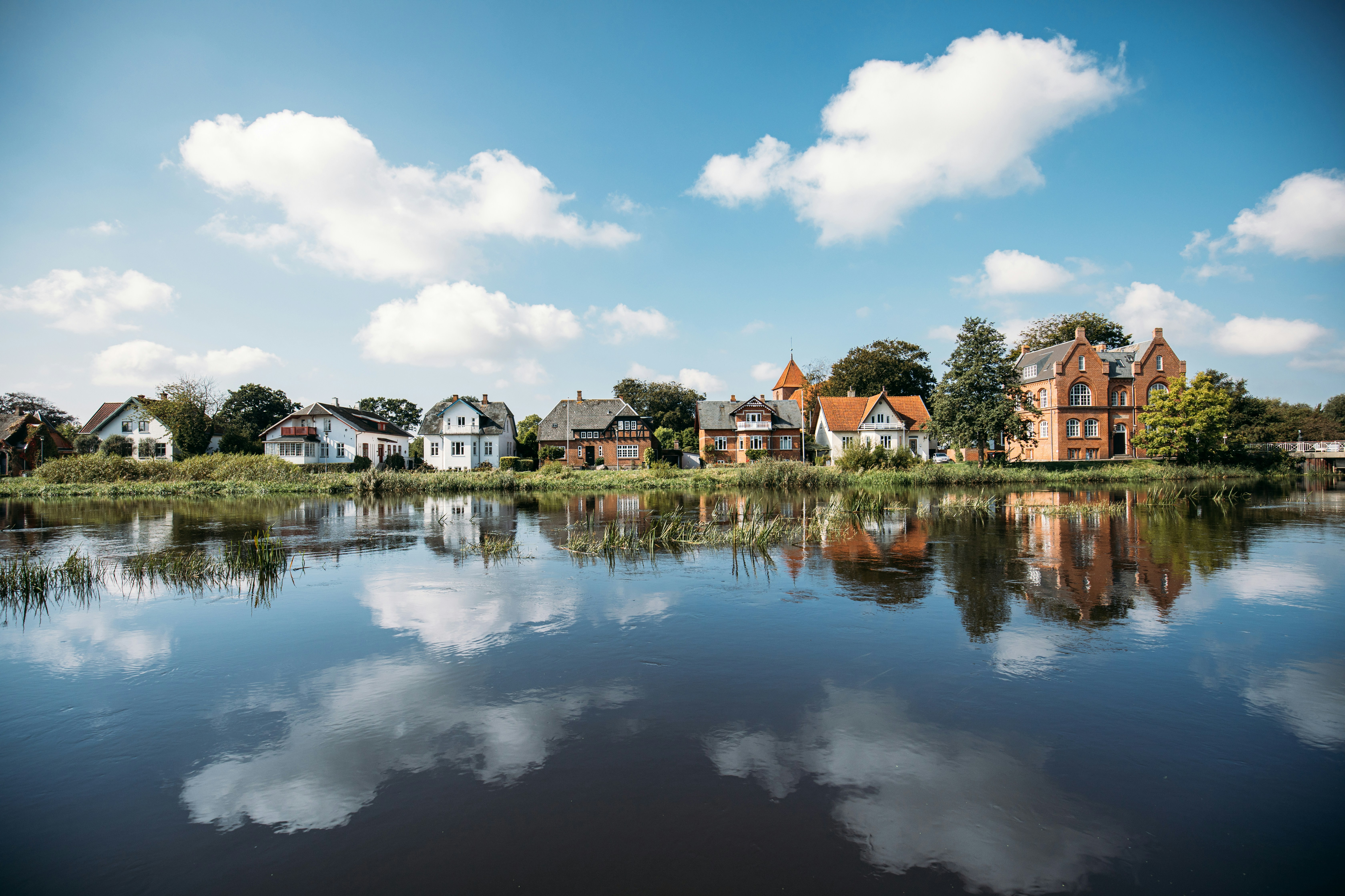 Village by the Glassy Lake under a Wide Blue Sky