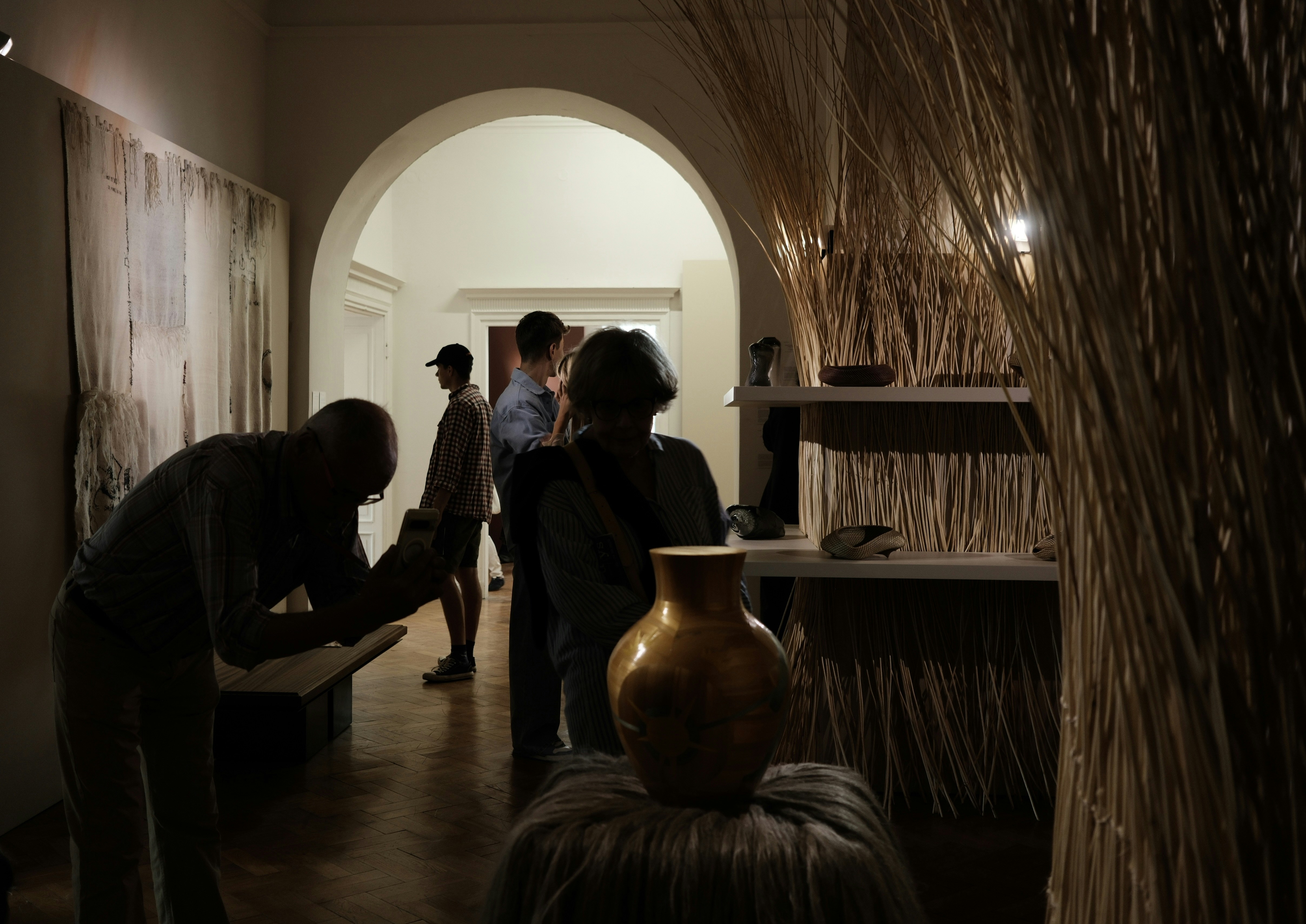 Arcade of Echoes: Visitors in a Dim Gallery Framed by a Central Arch