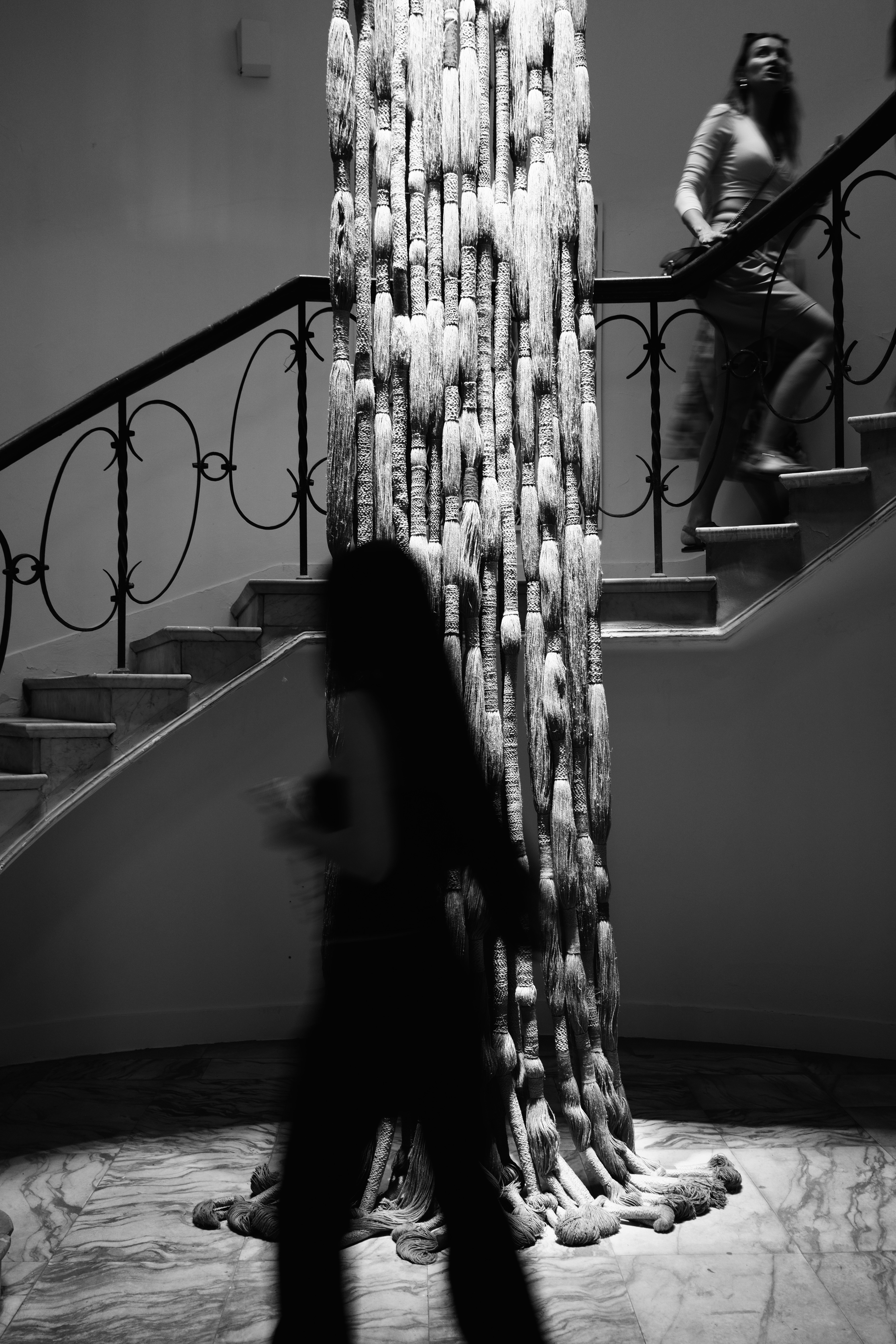 Shadowed Passage: A Motion of Silhouettes Around a Central Sculptural Column