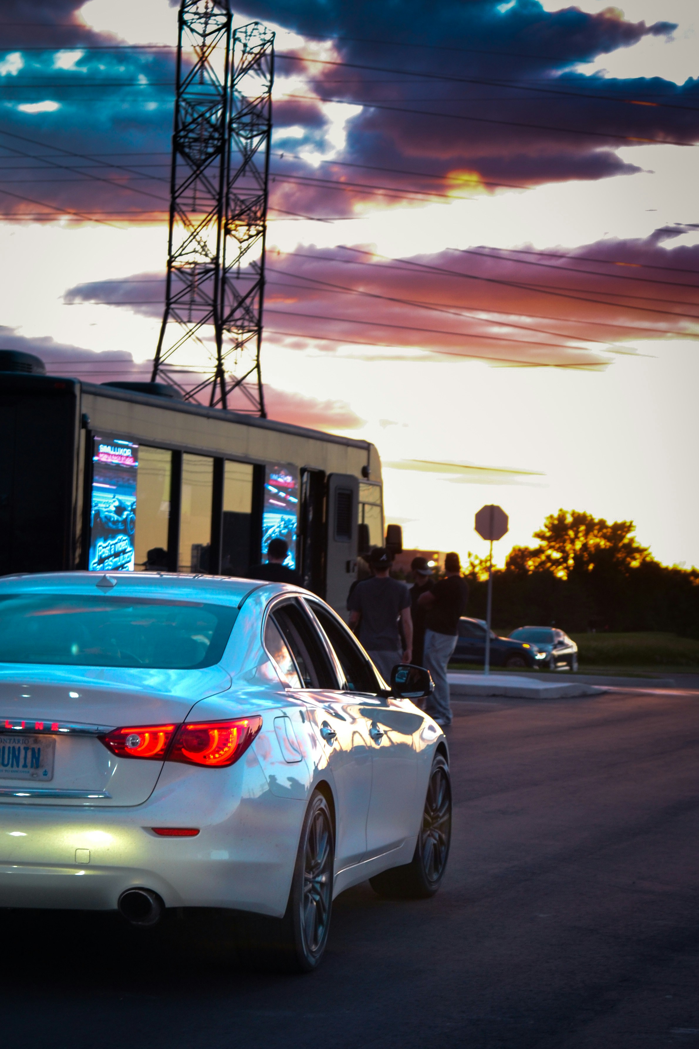 Silver sedan at sunset: reflections and motion by the bus