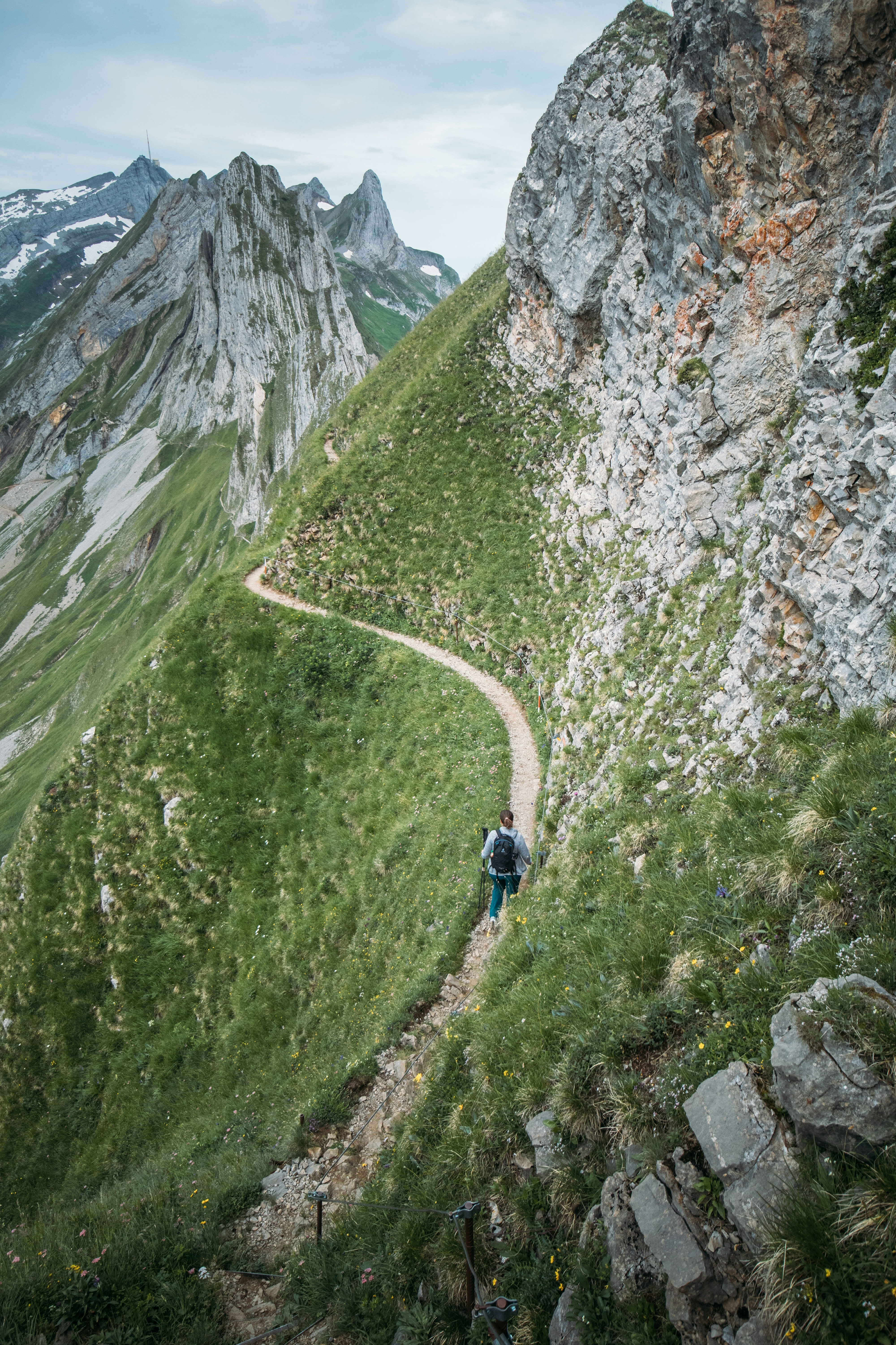 Hiker on a Knife-Edge Trail Clinging to the Mountain Ridge