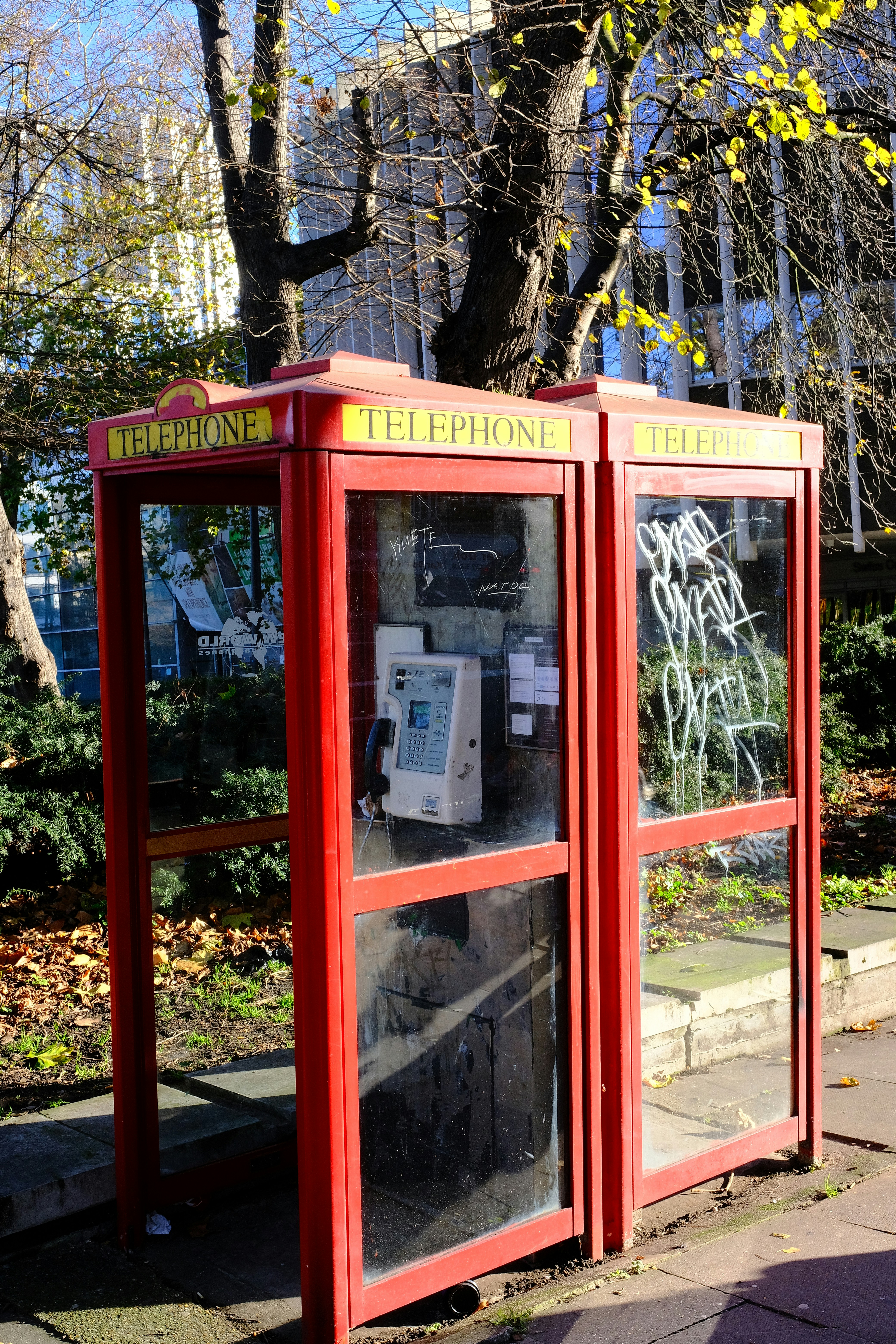 Red Kiosk Chorus: A Street Phone Booth on a City Sidewalk