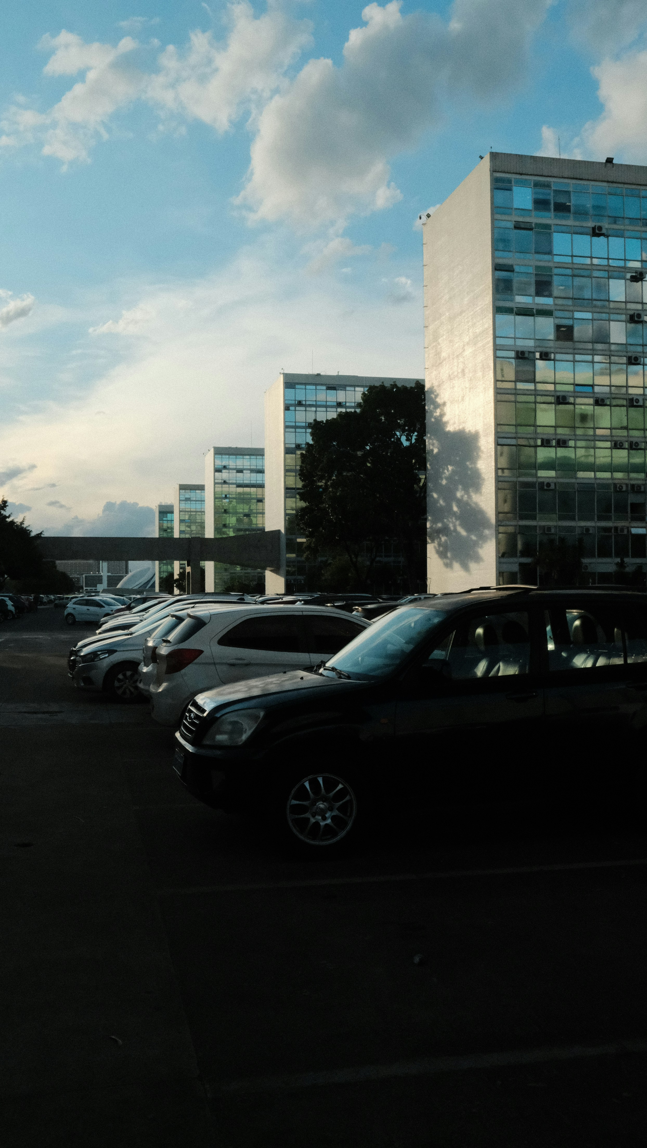 Parking tower silhouettes under a glass-clad campus