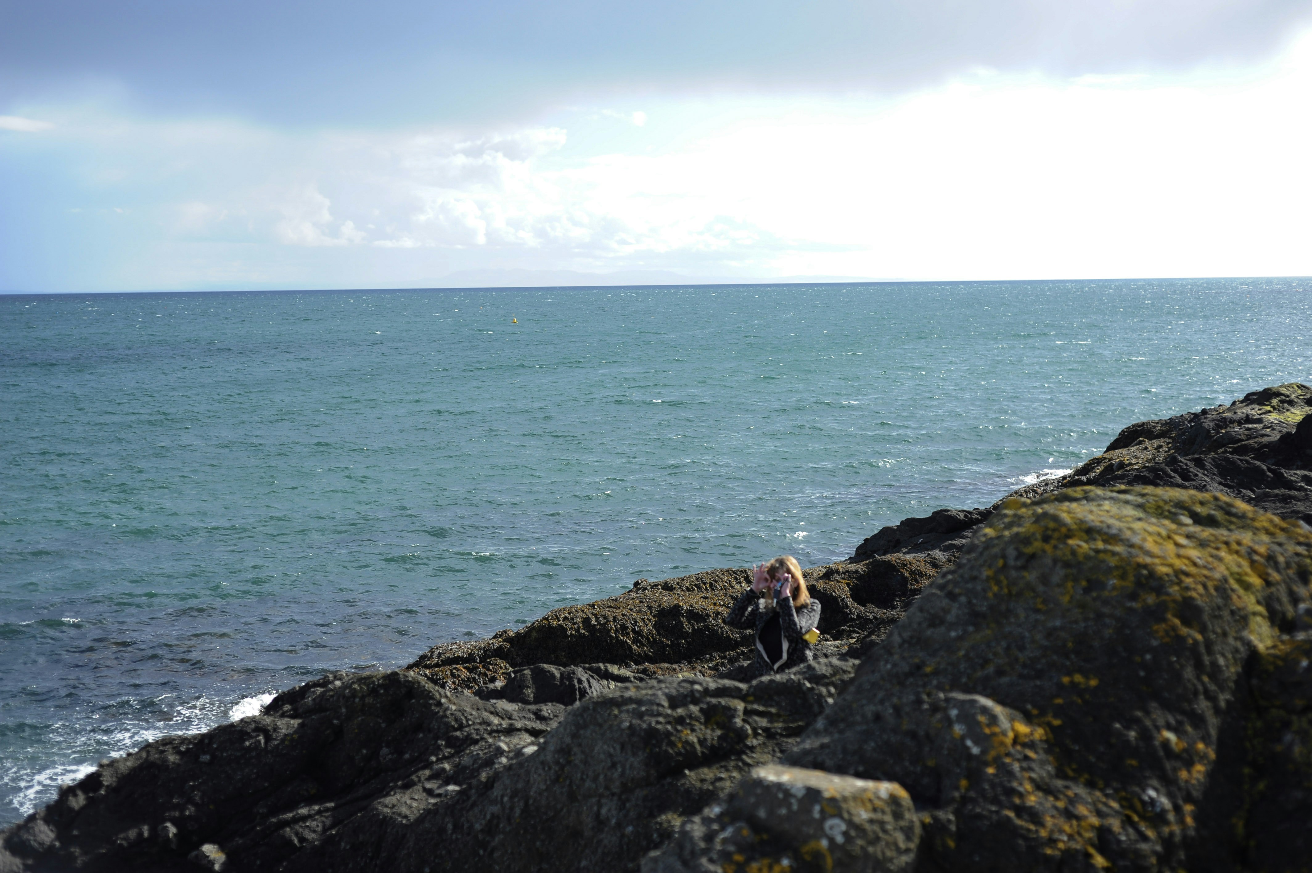 Lone Figure on Weathered Rocks Overlooking the Sea