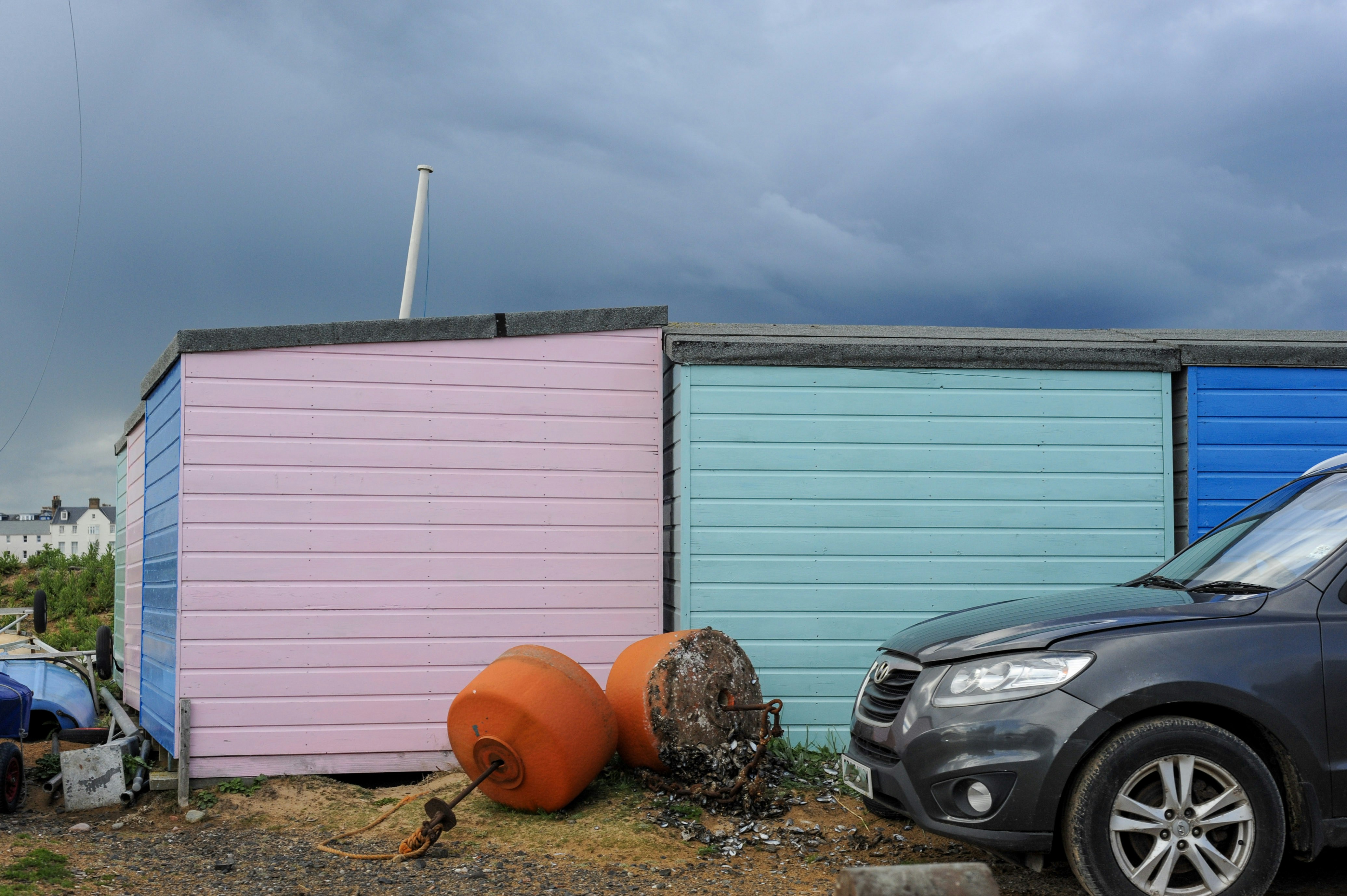 Coastal Color Blocks: A Quiet Shoreline Backdrop by a Parked SUV