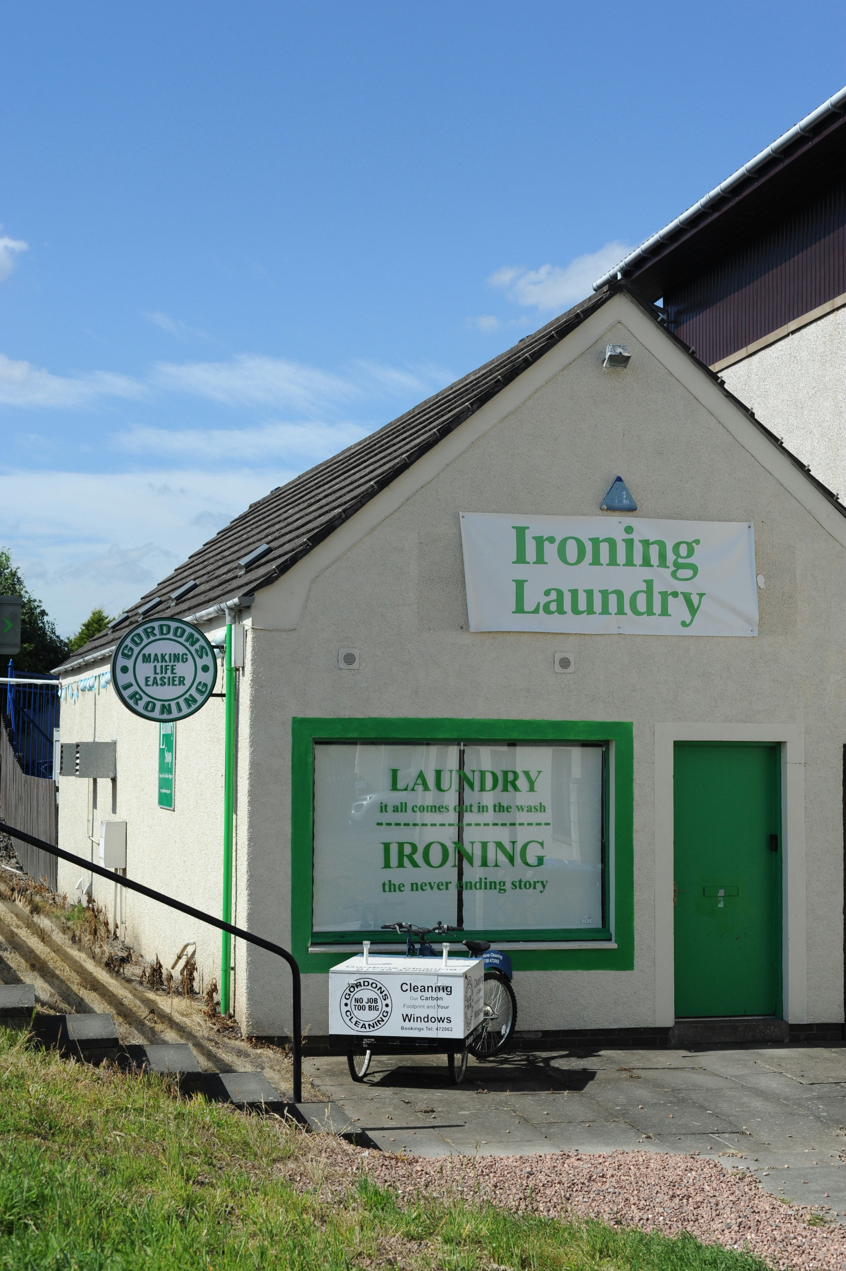 Ironing Laundry: A Small Shopfront with Green Accents and a Mobile Cart