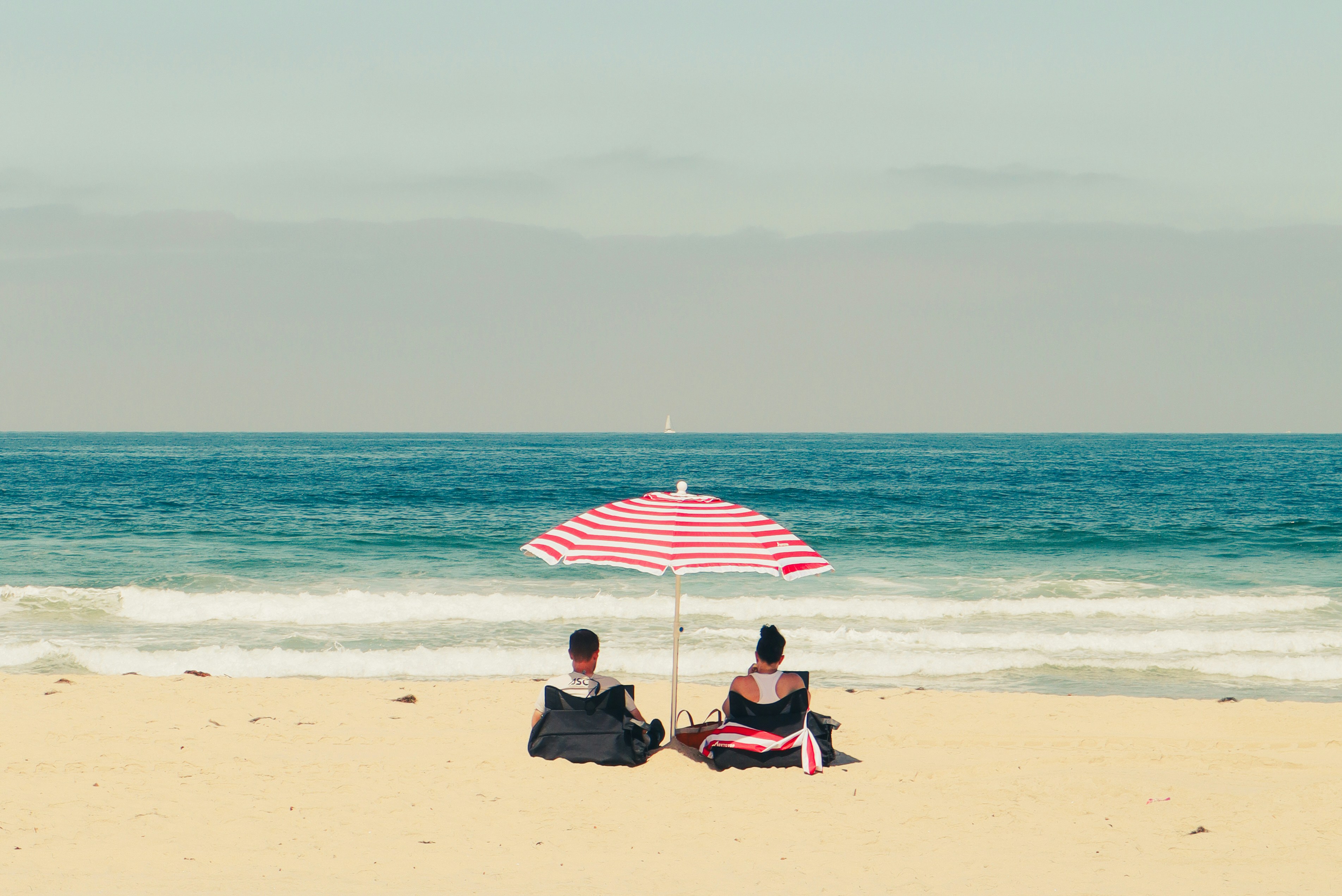 Stranded beneath a striped parasol: quiet beach moment at shore