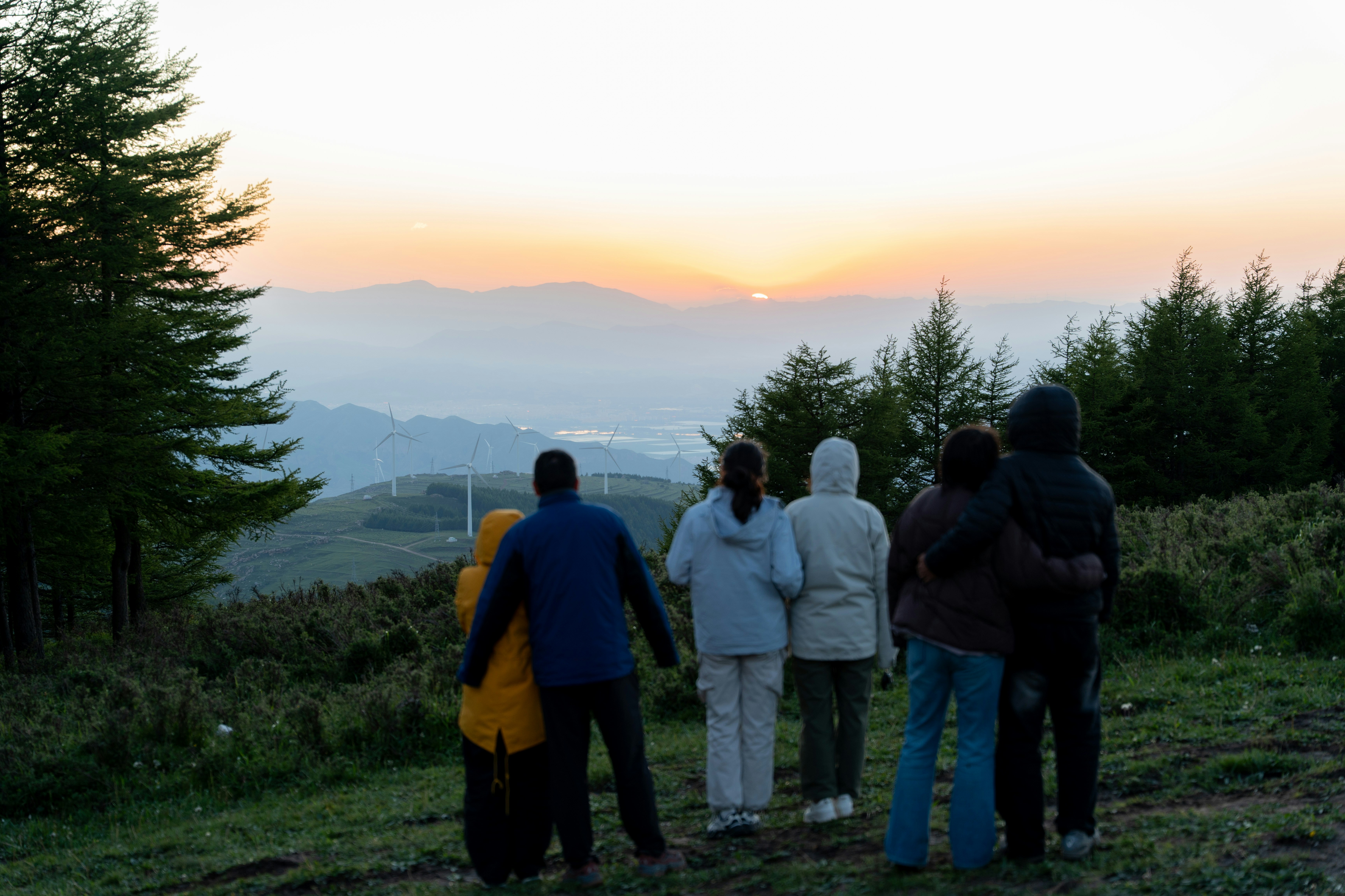 Sunset Watchers on the Highland as Distant Wind Turbines Fade into the Valley