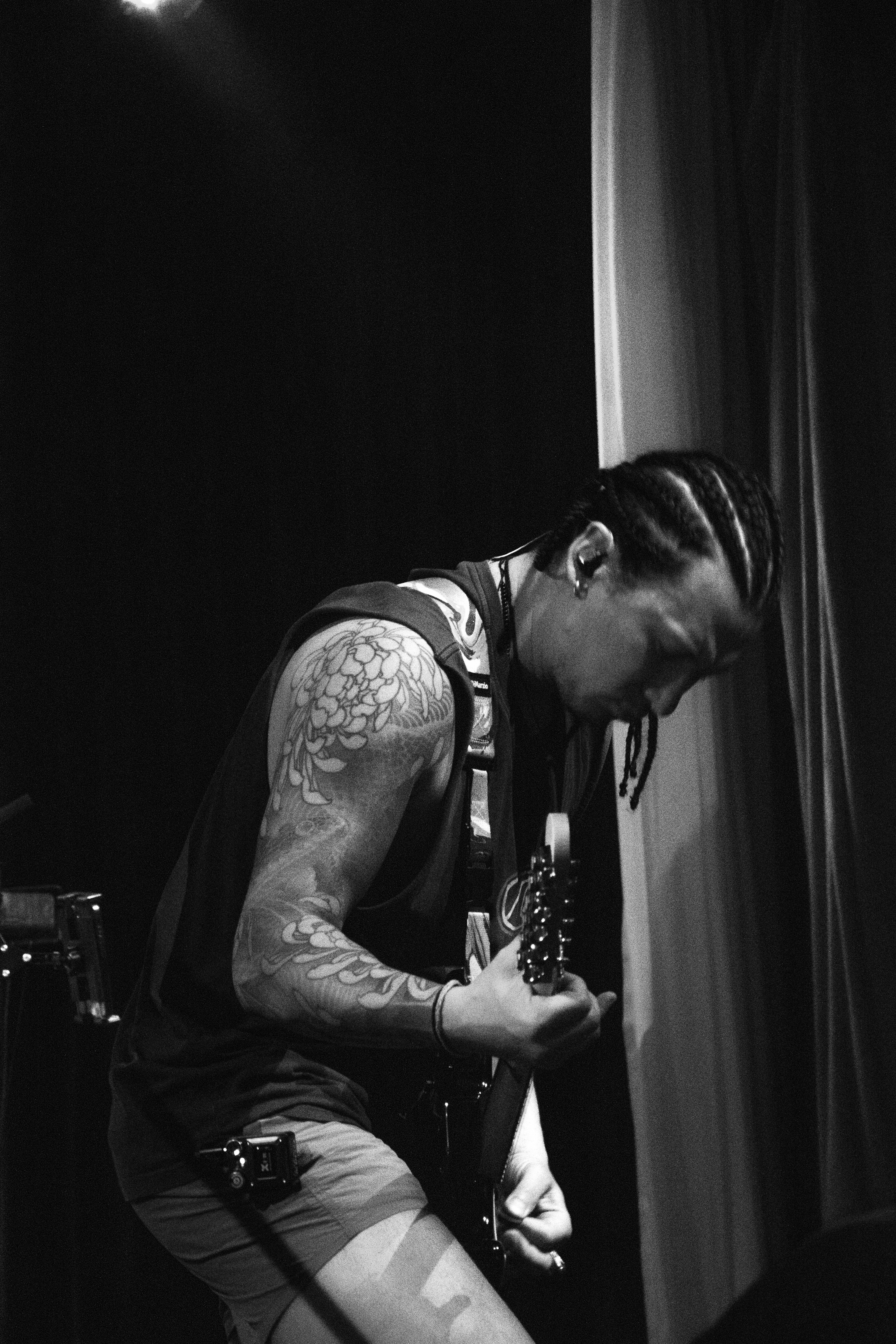 Guitarist in Shadow: Tattoos, Focus, and a Quiet Stage Moment