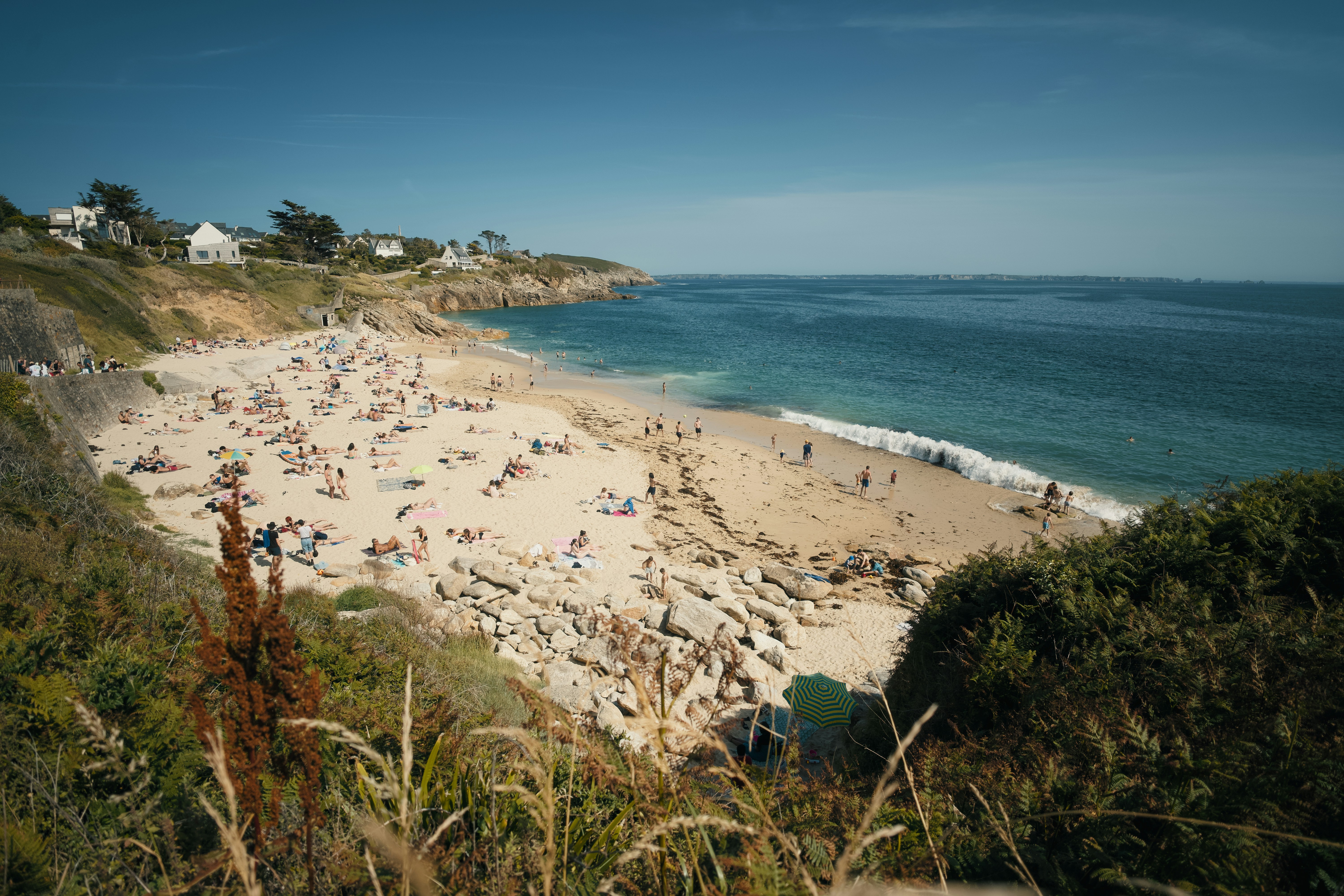 Sunlit Cove: A Curving Beach Busy with Summer Rays