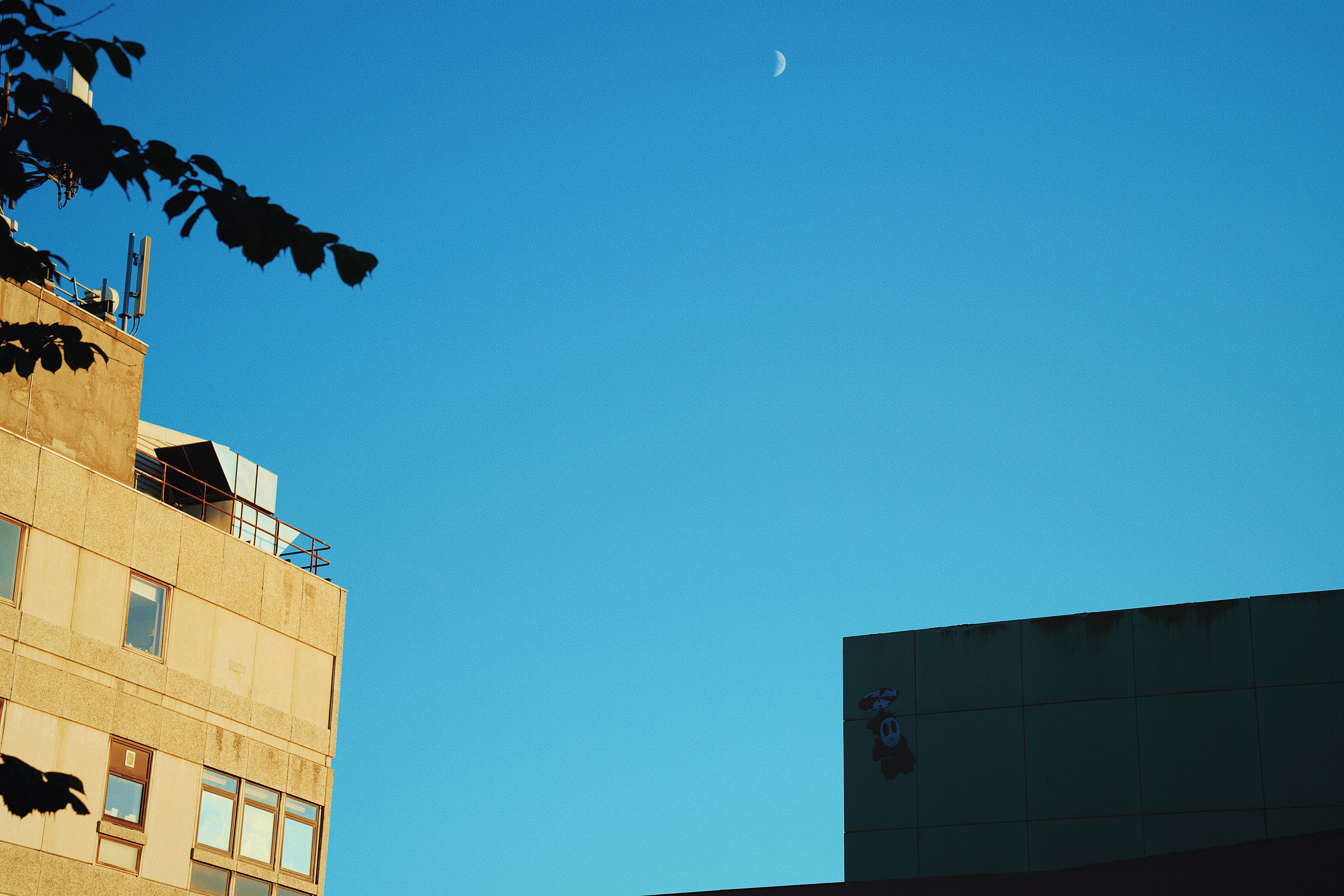 Blue Sky Over City Facades with Crescent Moon