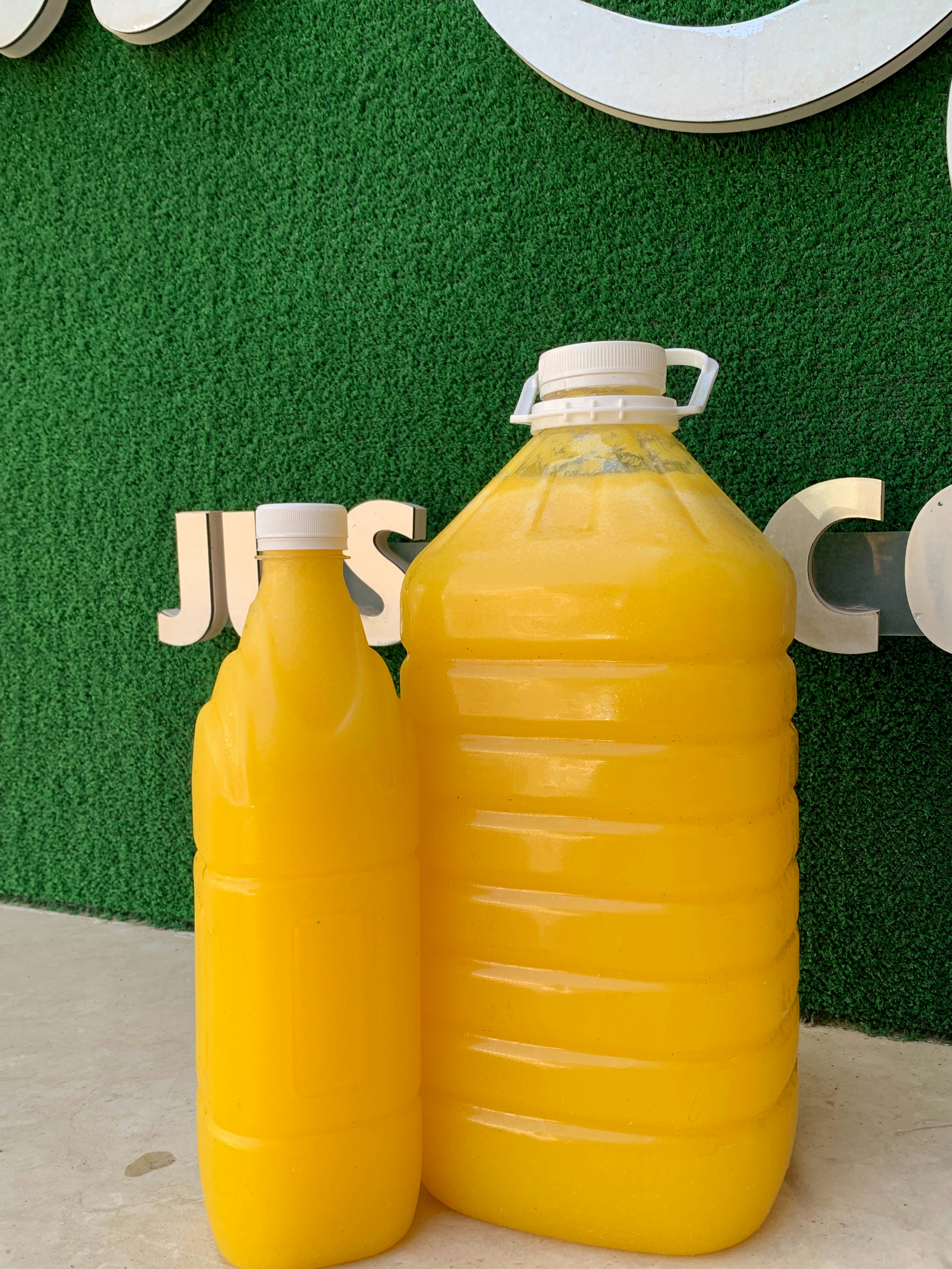 Two Golden Bottles Stand Tall Against a Green Wall