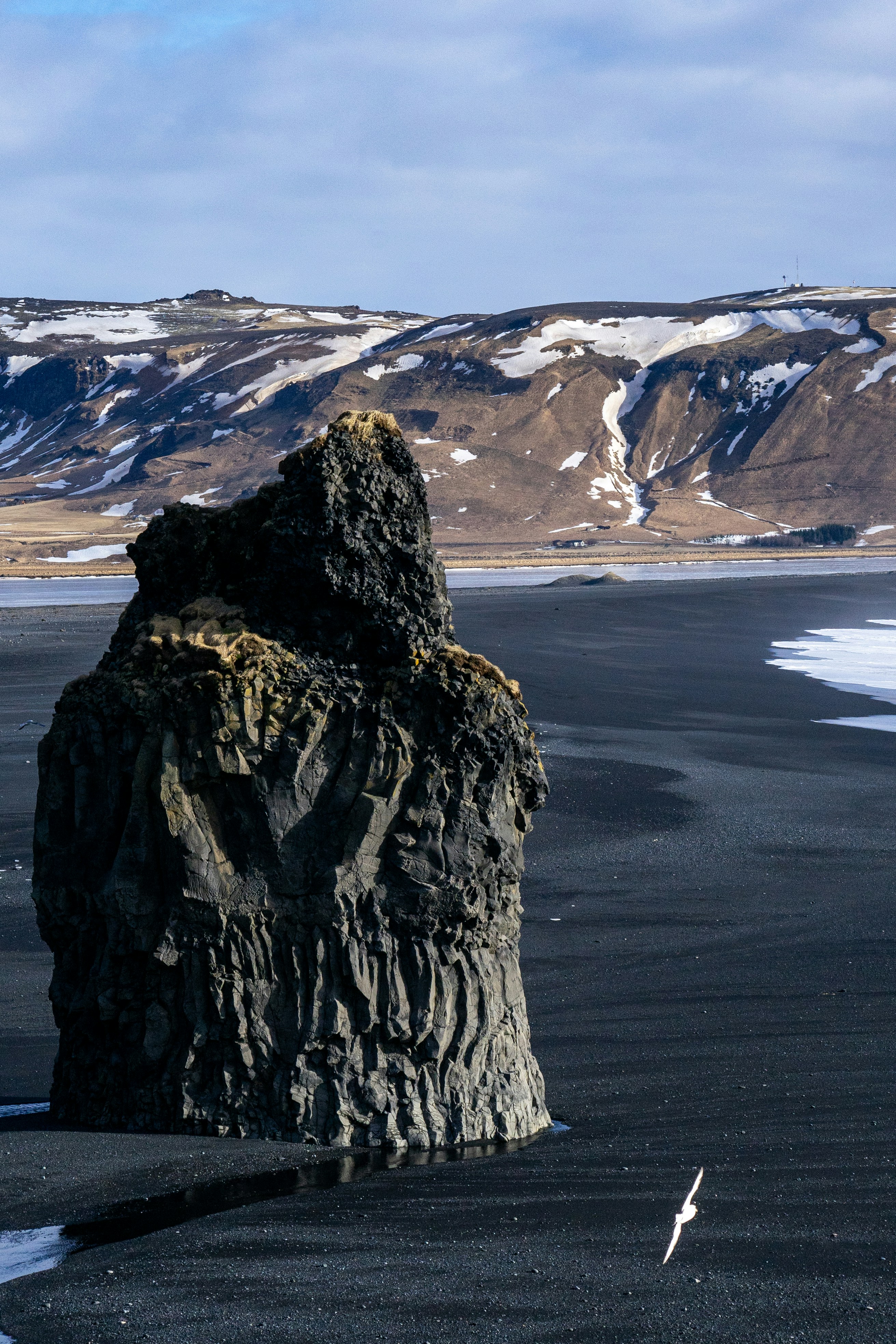 Towering Basalt in a Snow-Fringed Black Sand Coast