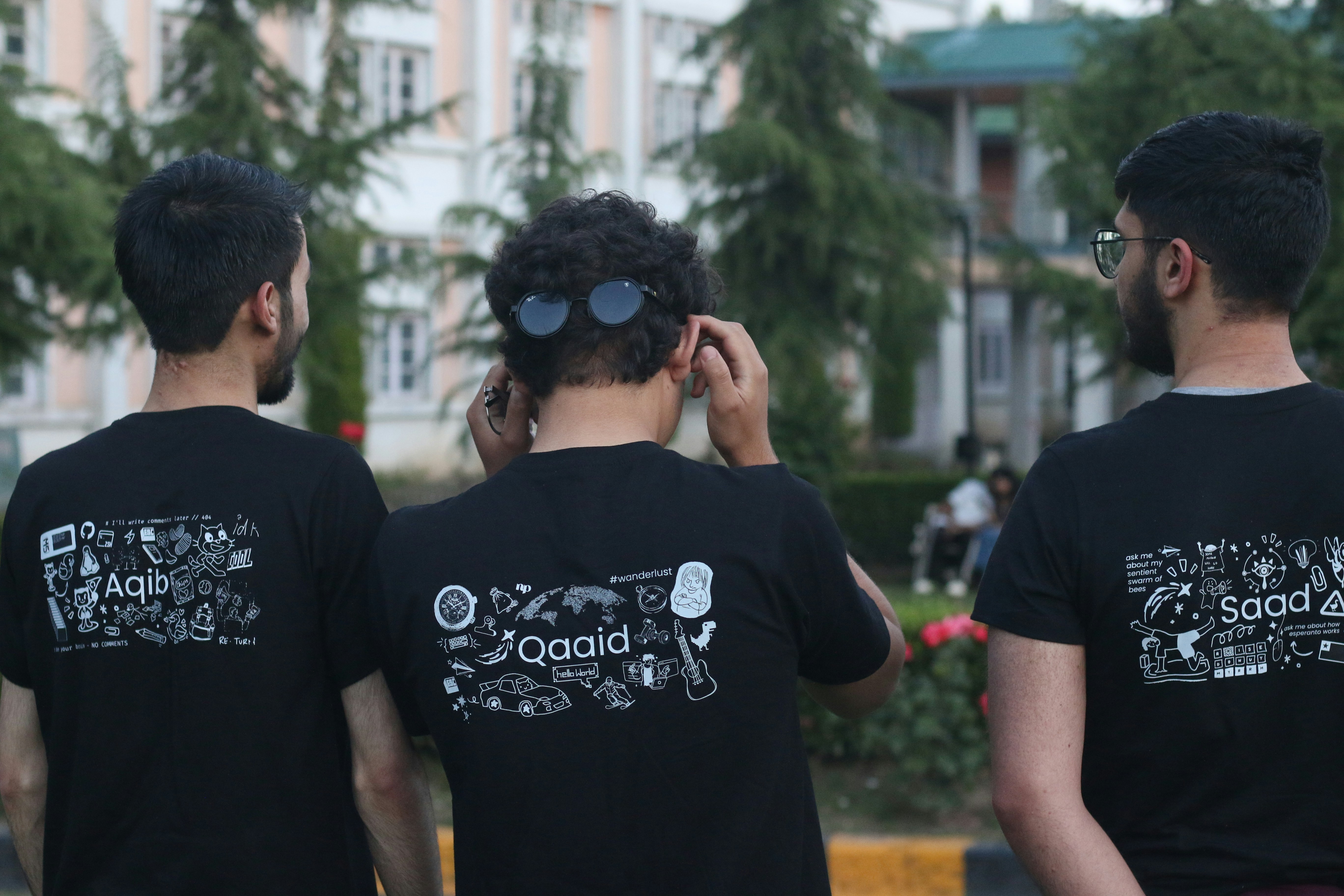 Three Friends in Matching Tees Overlooking a Courtyard