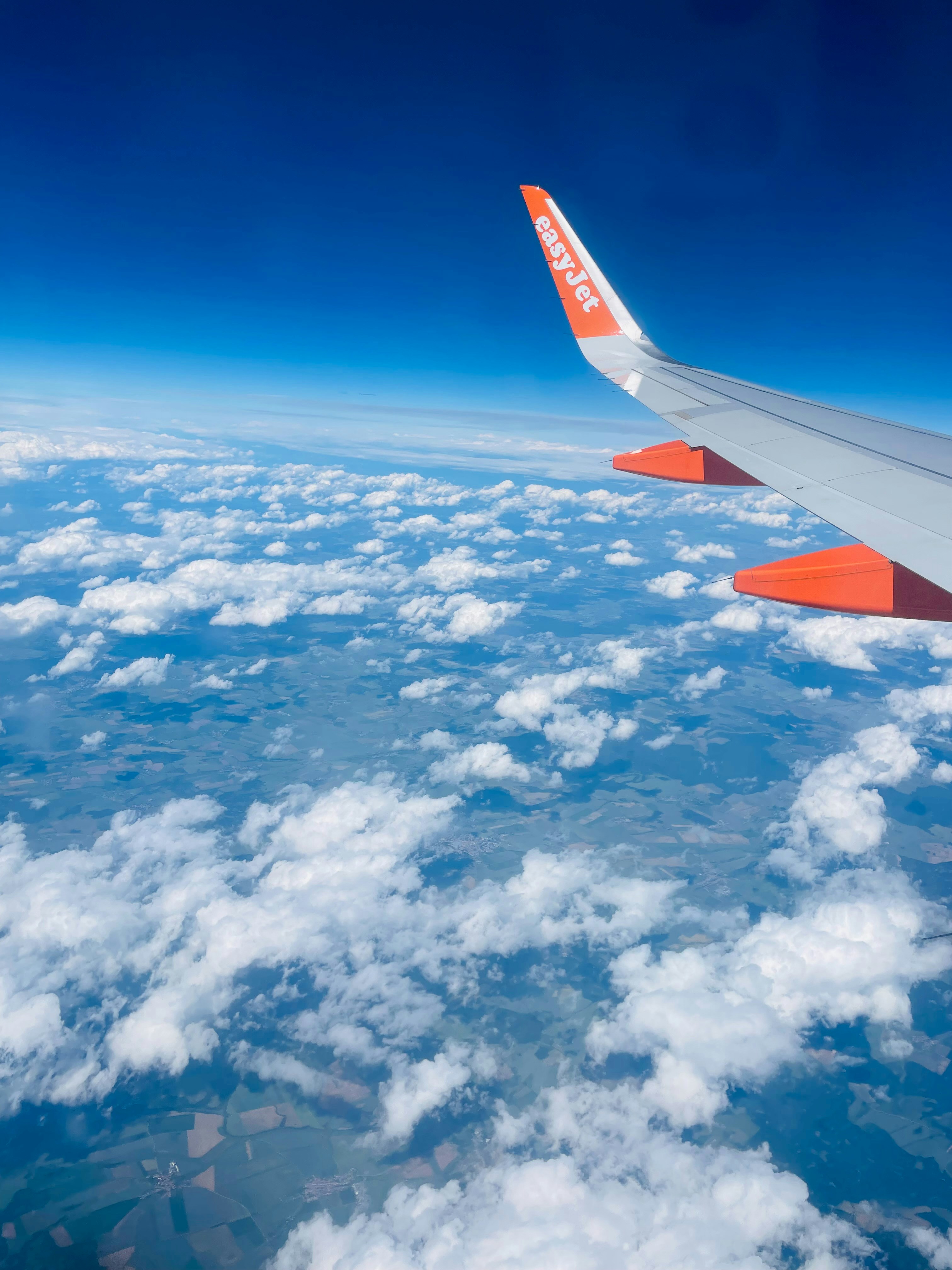 Orange-tipped wing slicing through a sea of clouds from a high-altitude vantage
