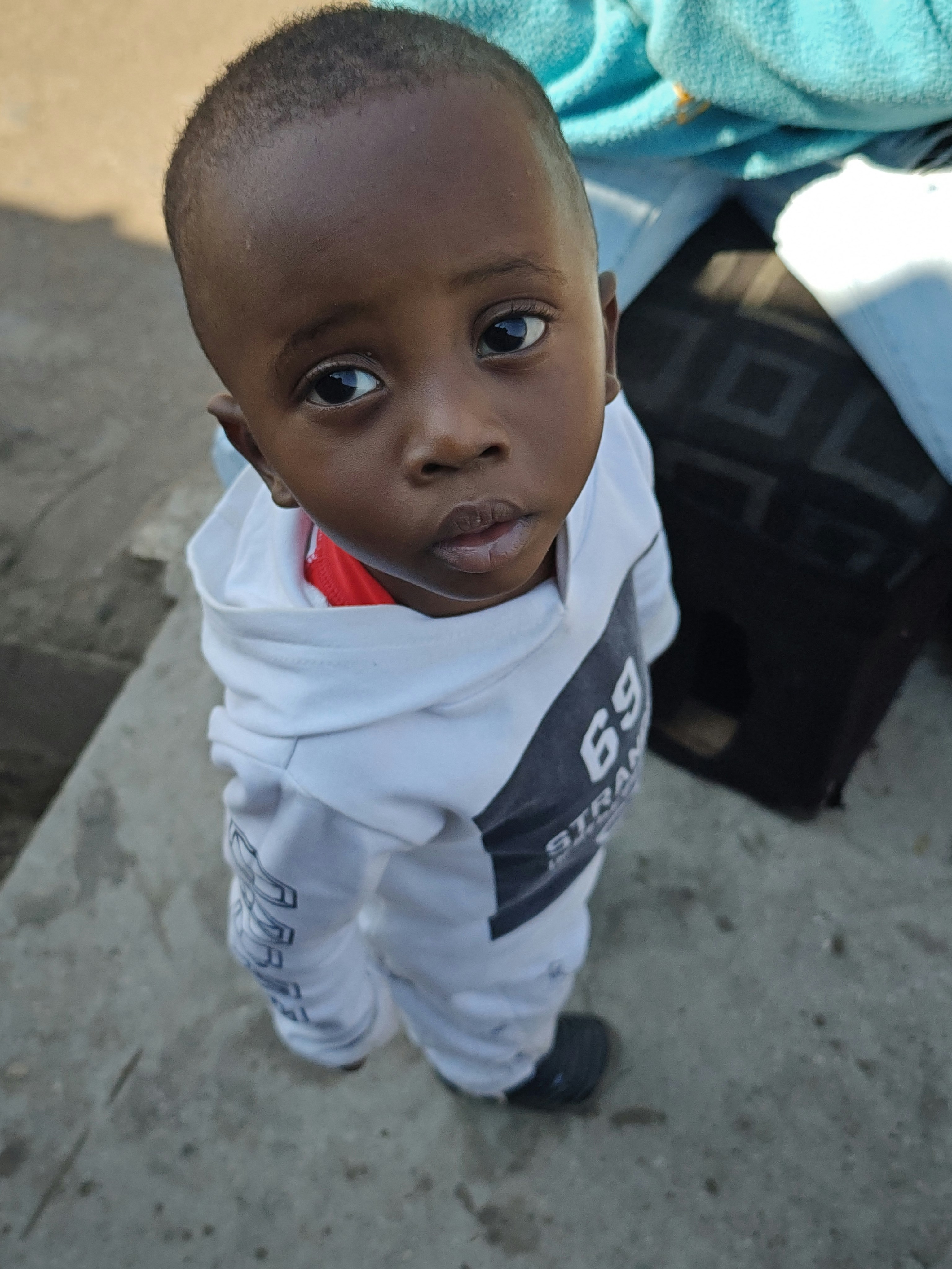 A curious gaze from above: toddler looks up from a sunlit street